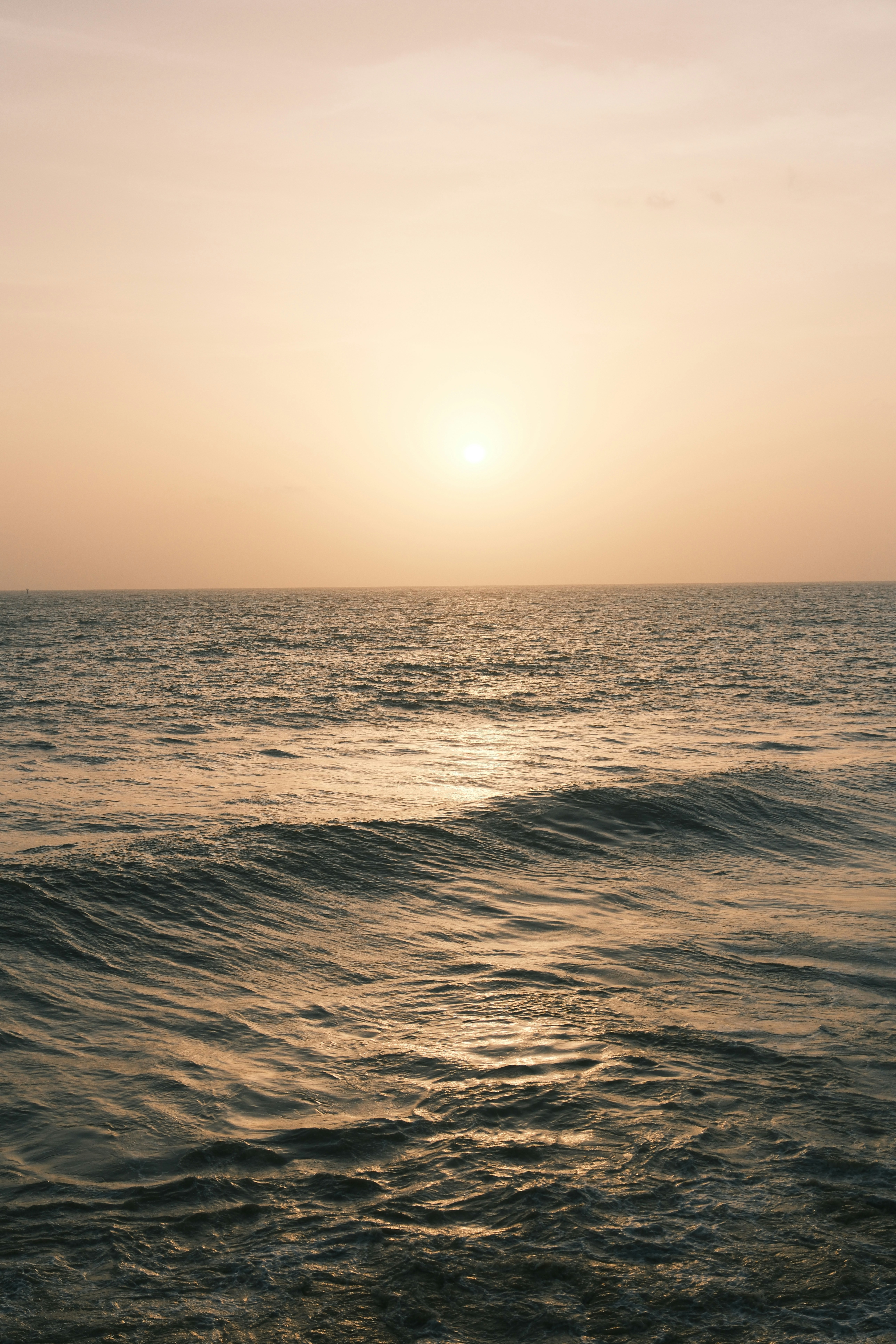 Sunset over the ocean with gentle waves.