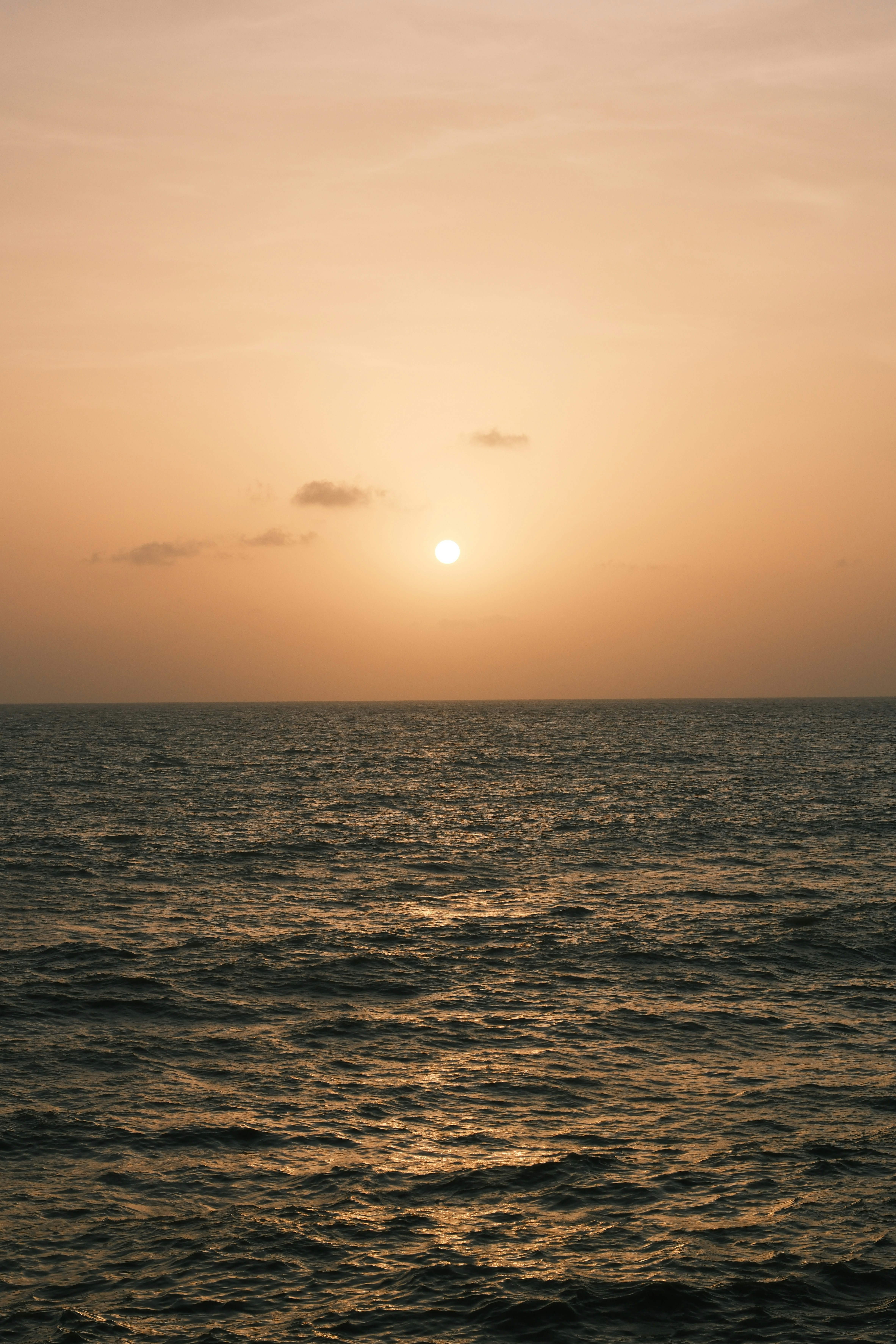 Sunset over a calm ocean with an orange sky.