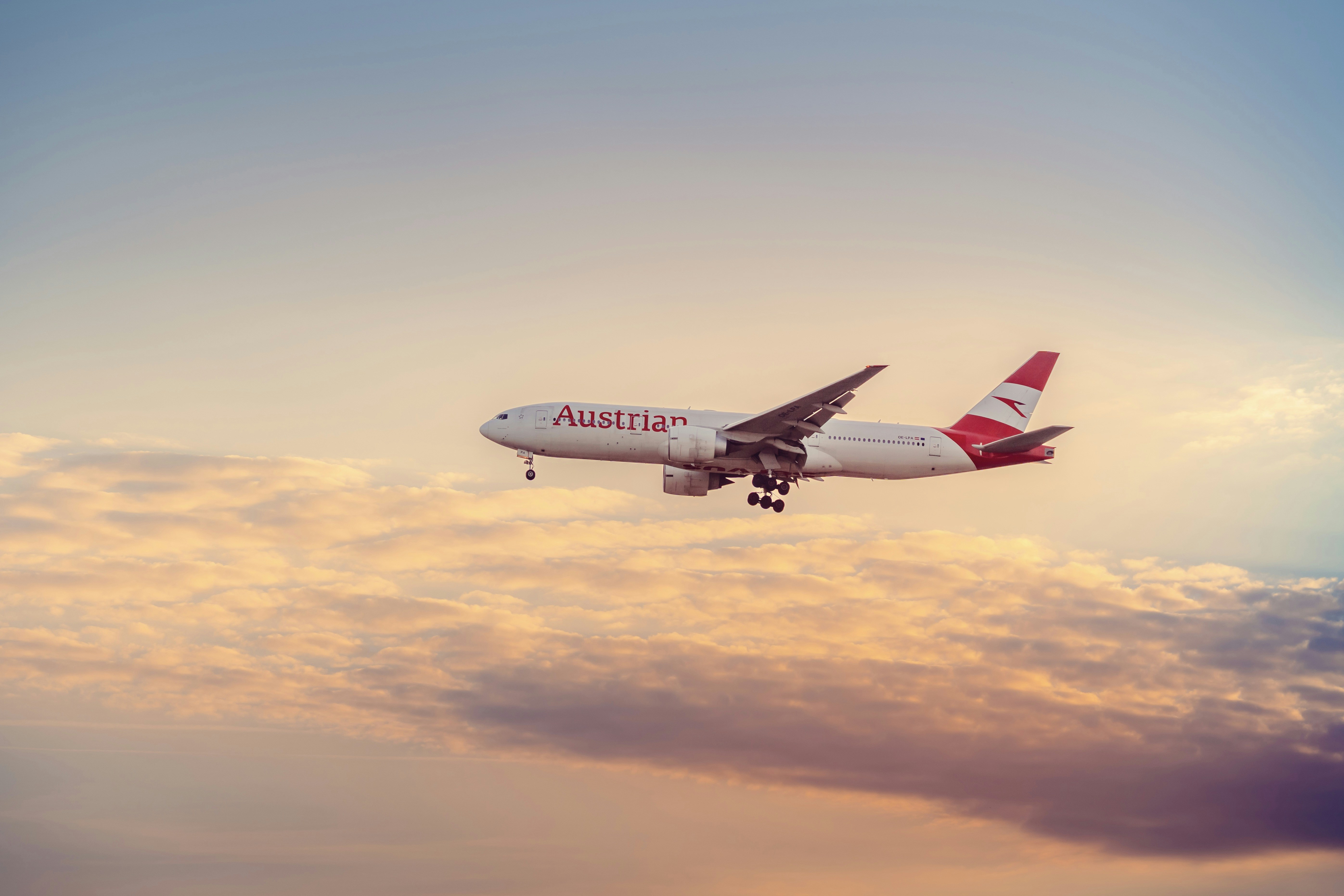 Azure descent: Austrian Airlines jet gliding over sunset clouds
