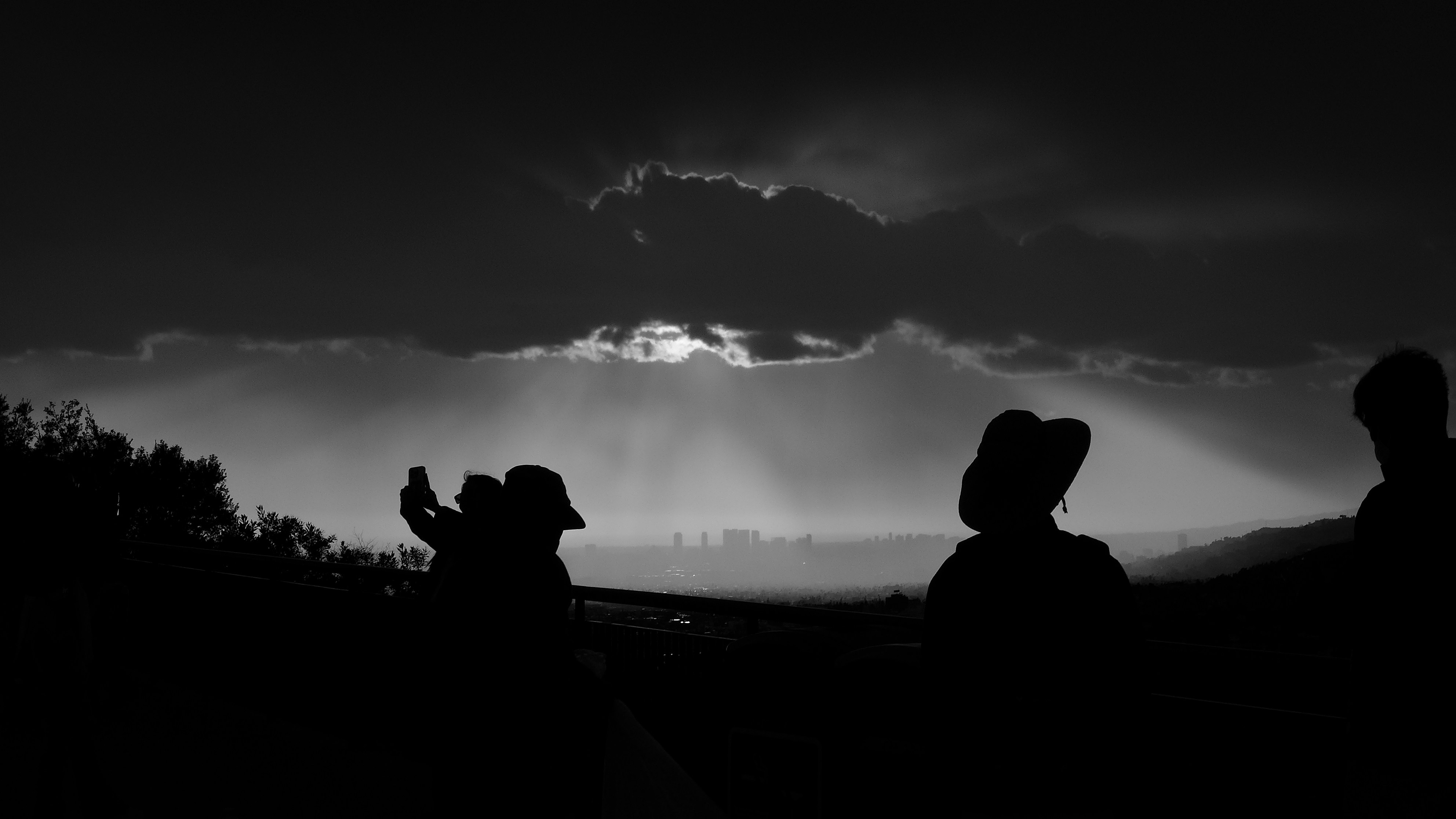 Silhouettes at Dusk: A Quiet Vista Beneath Sunlit Clouds