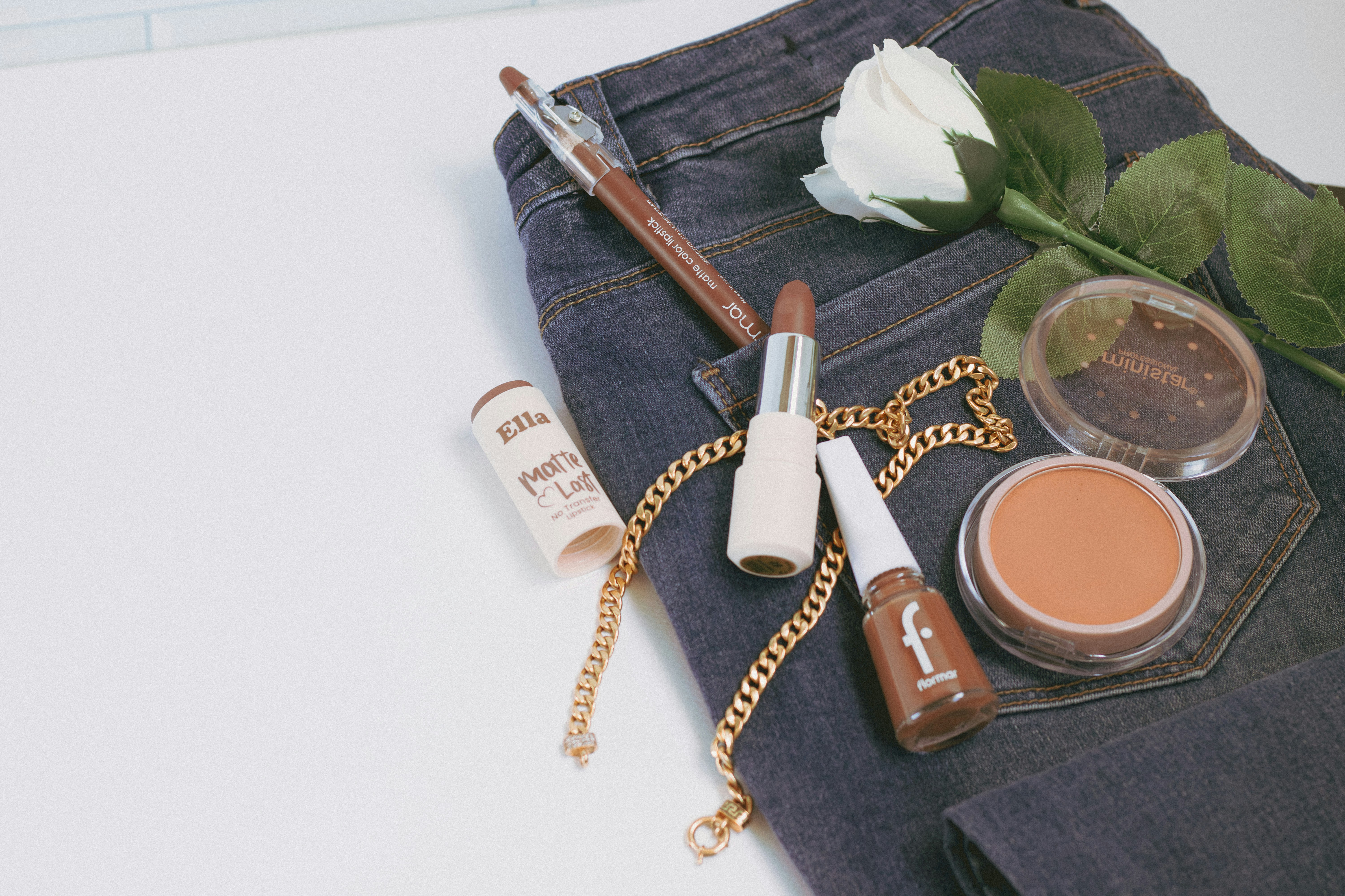 Cosmetics Suite on Denim: A Quiet Still-Life with Lipsticks and Rose