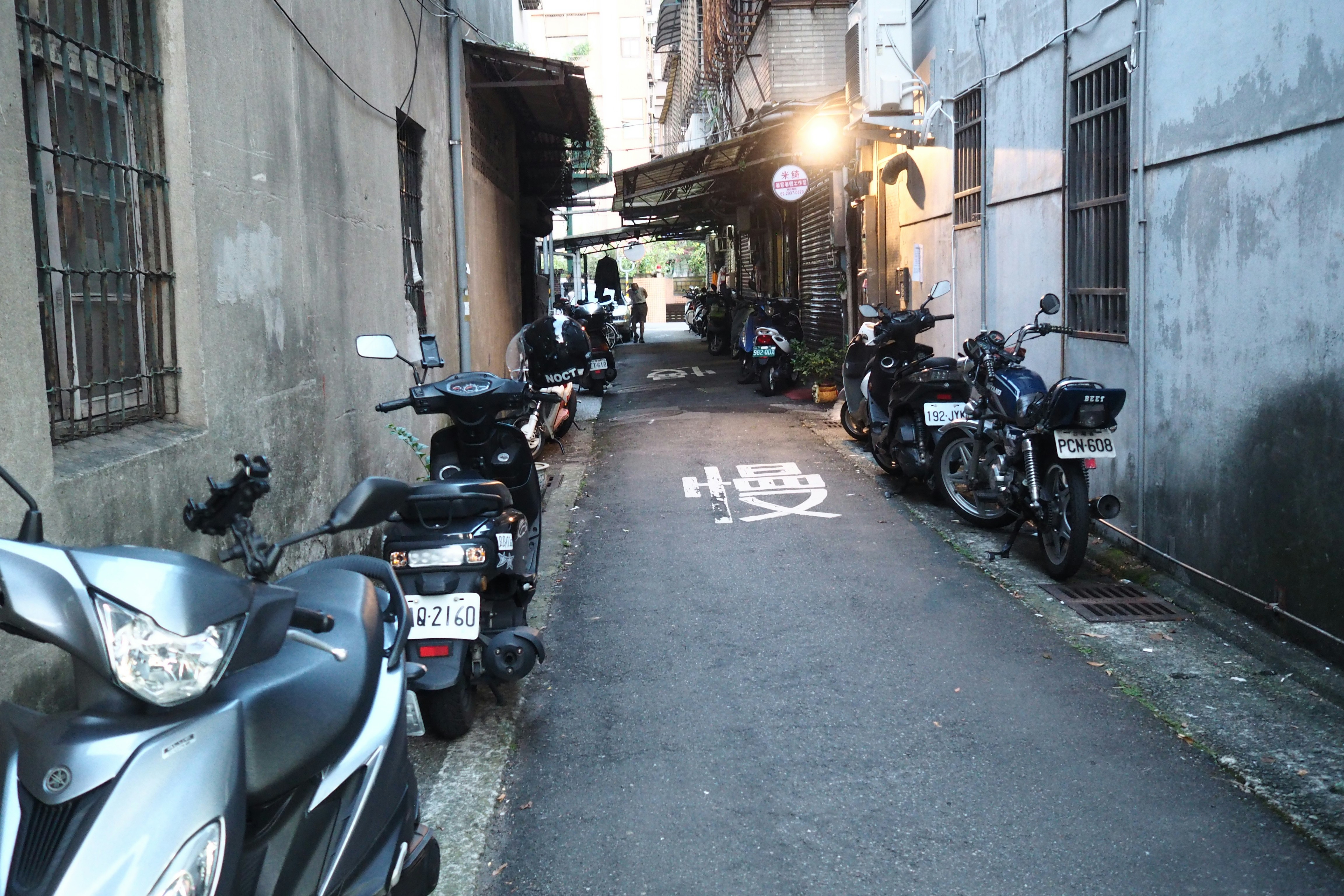 Narrow Alleyway Saturated with Scooters Under Warm Streetlight