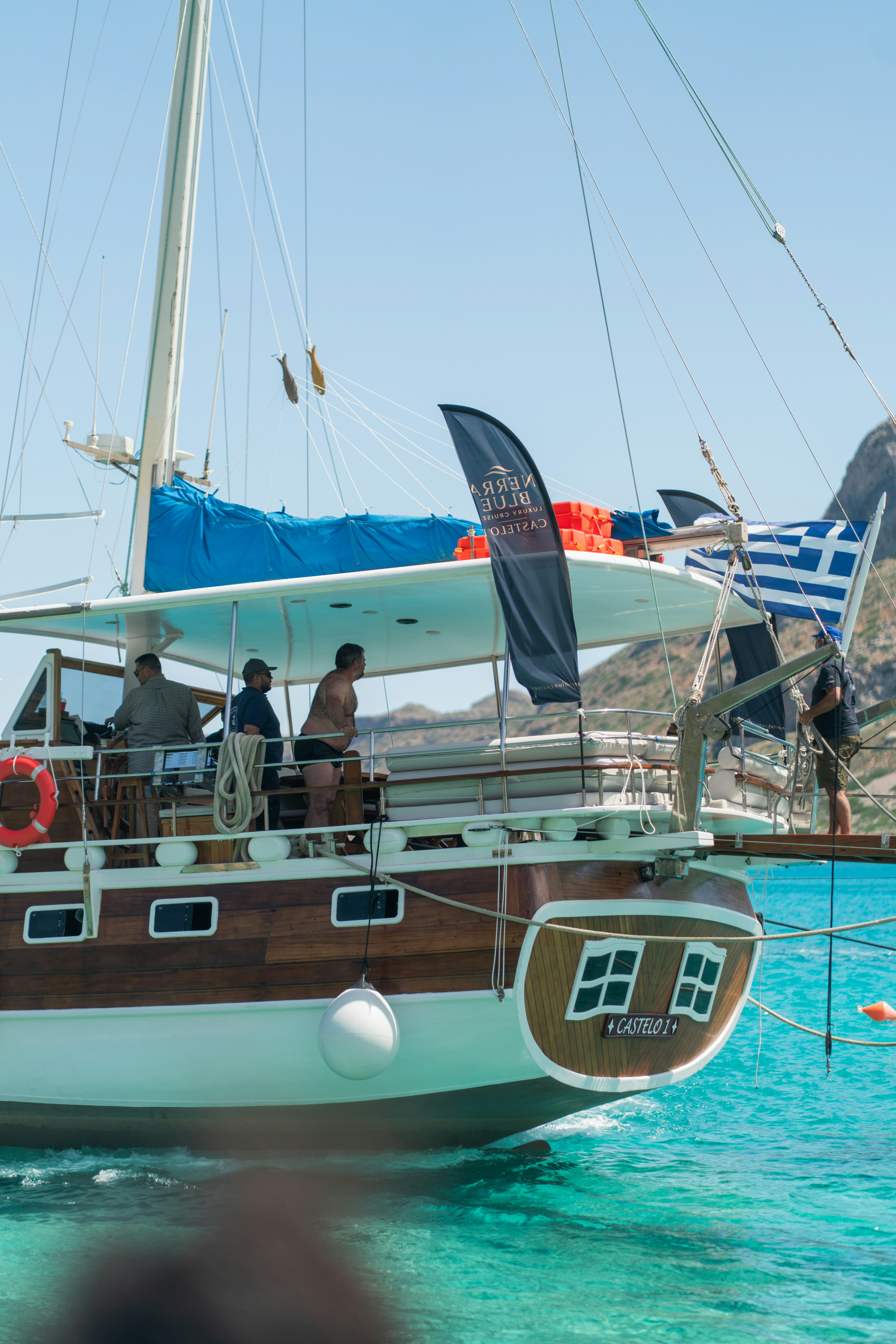 A large wooden boat with passengers in turquoise sea.