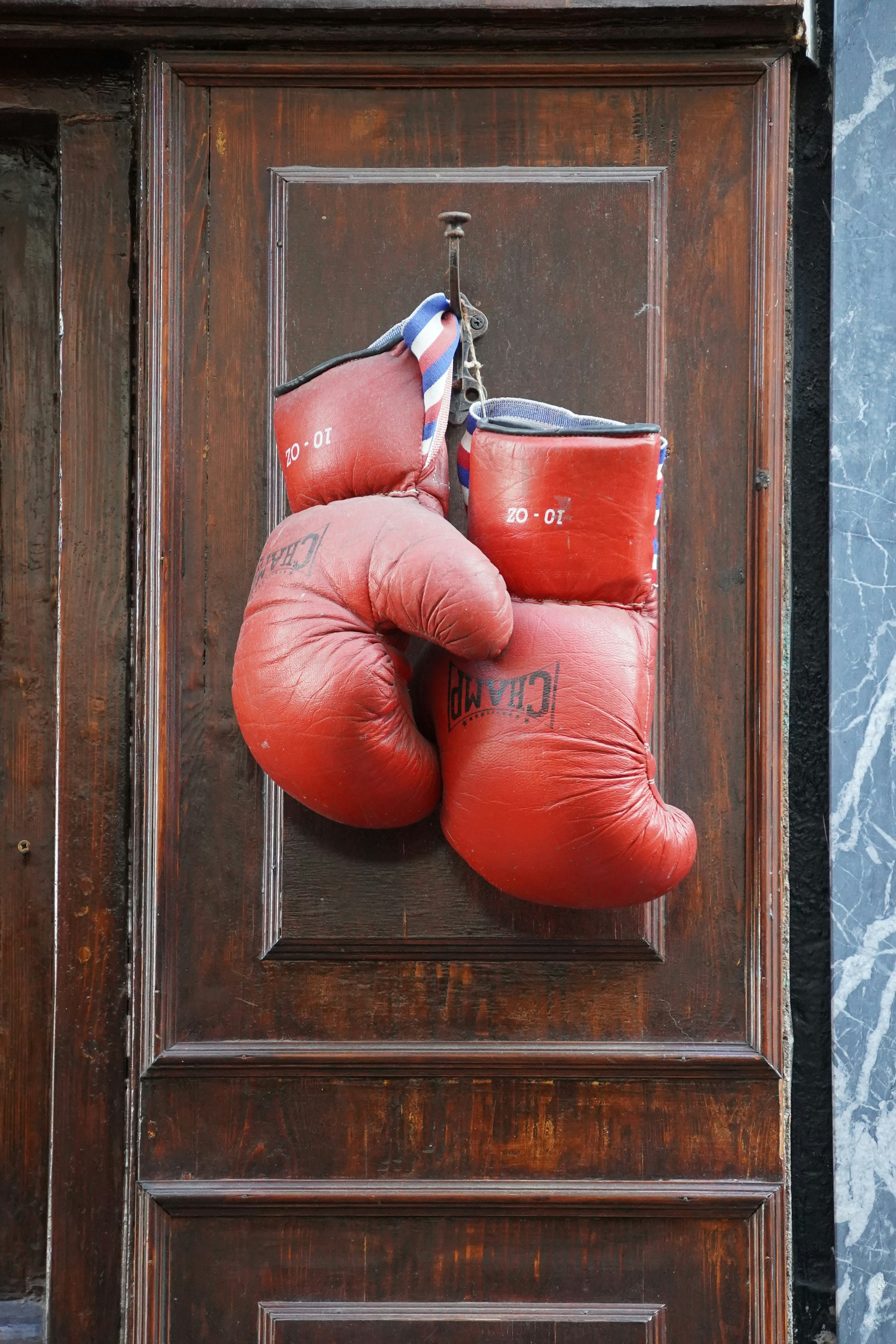 Red Boxing Gloves Adorning a Rustic Door Knocker