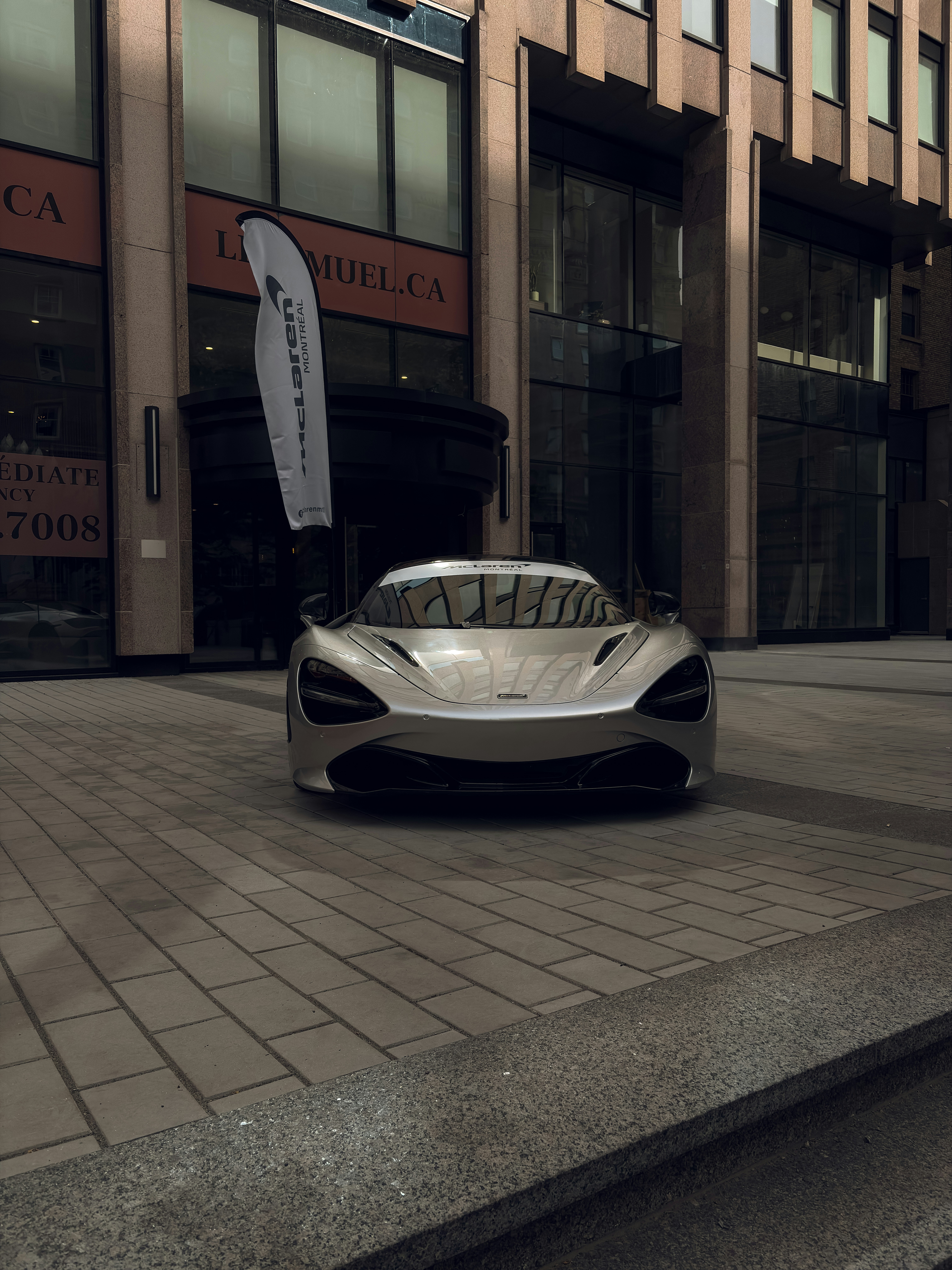 Low-Angle Silver Hypercar Guarded by Urban Facade