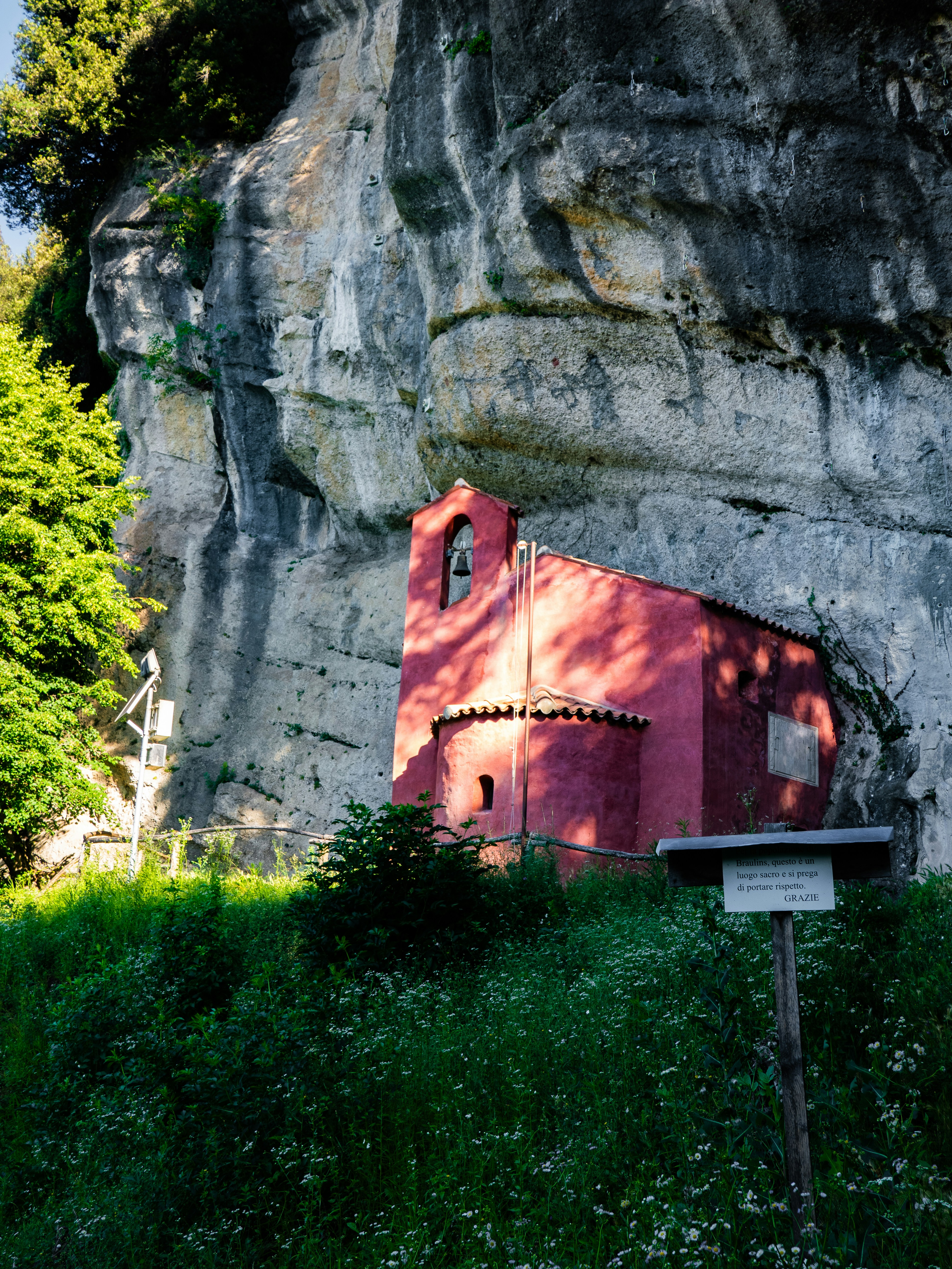 Red chapel built into a large rock cliff.