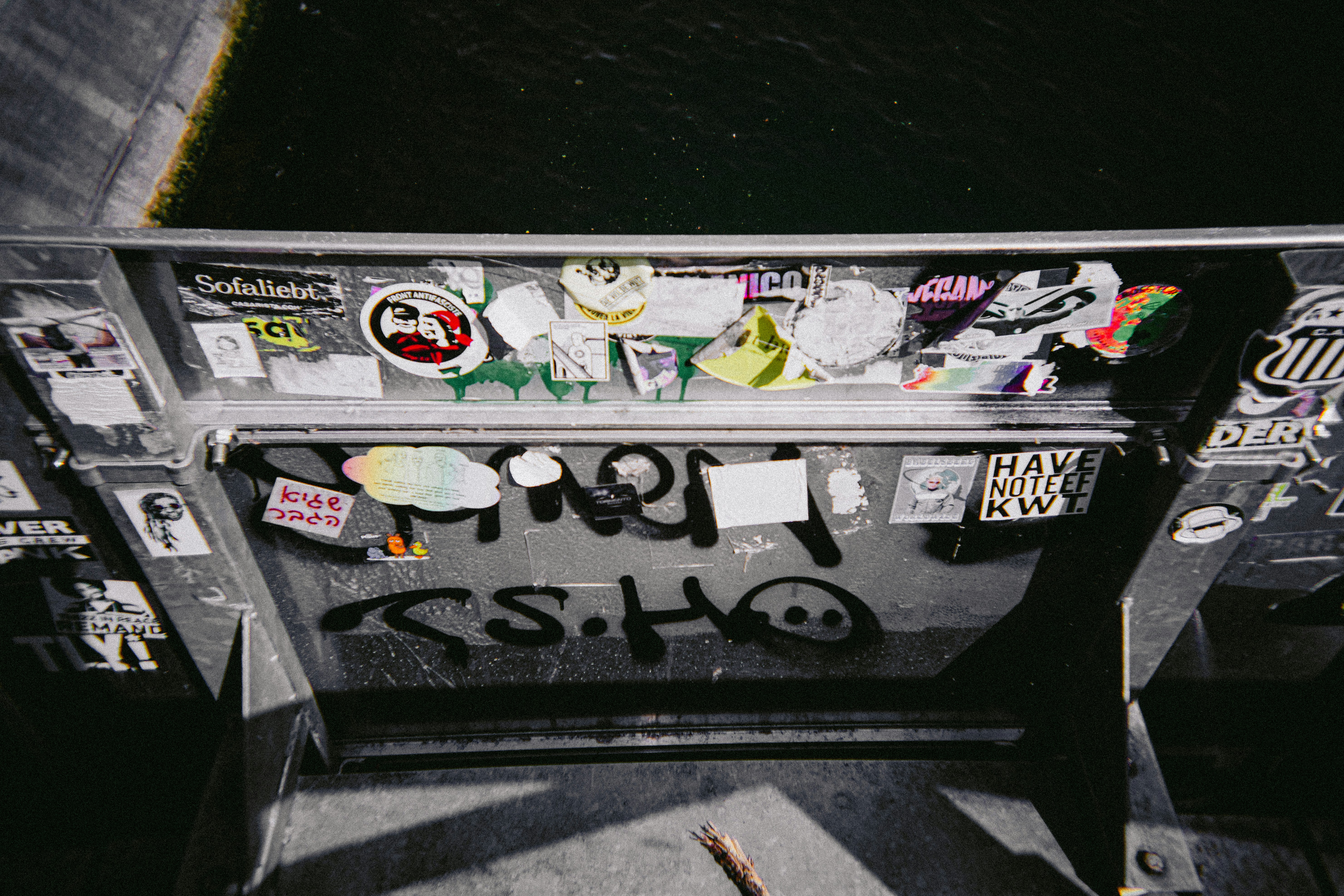 Stickered metal ledge with graffiti and worn surfaces
