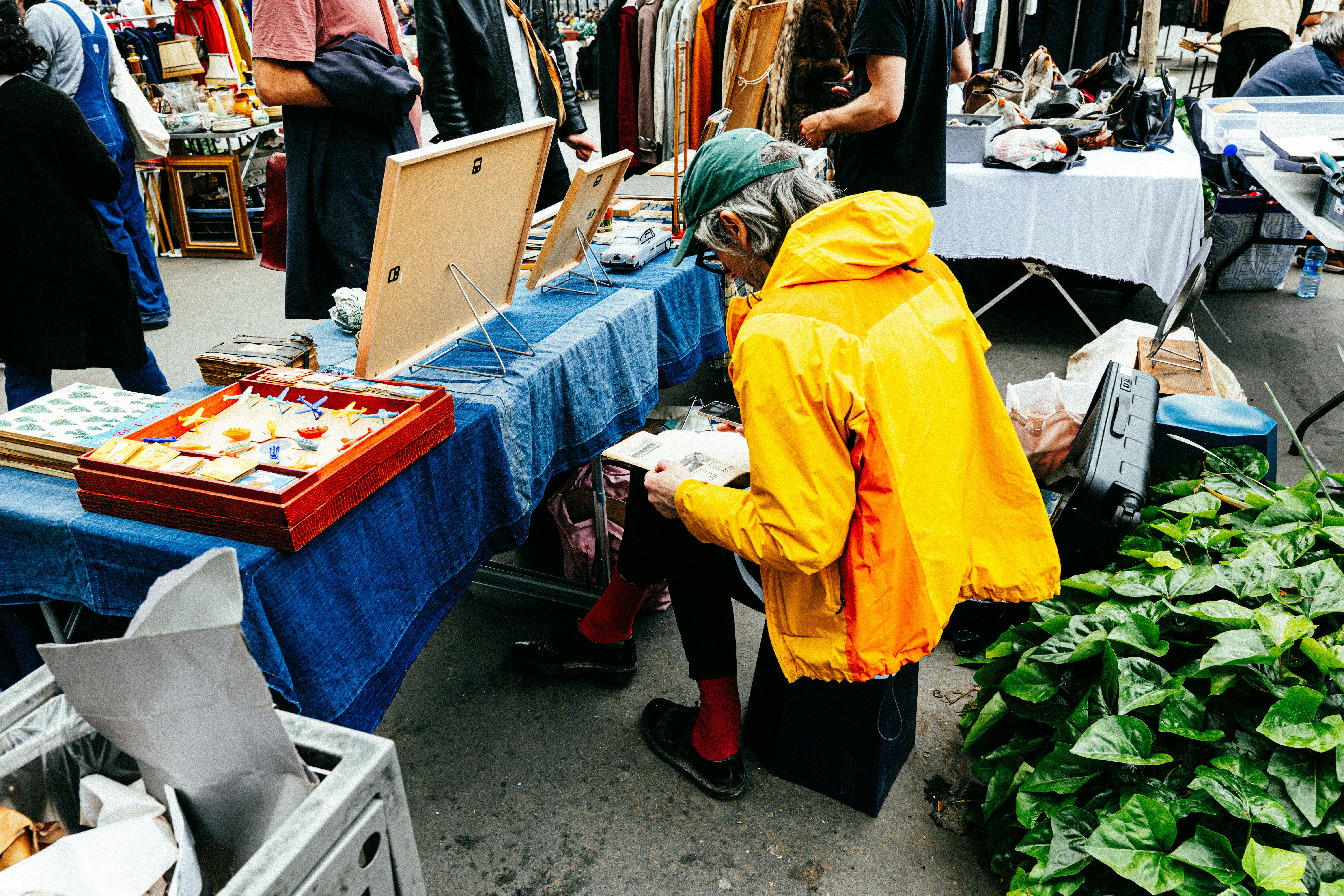 Person in yellow jacket sits at an outdoor market.