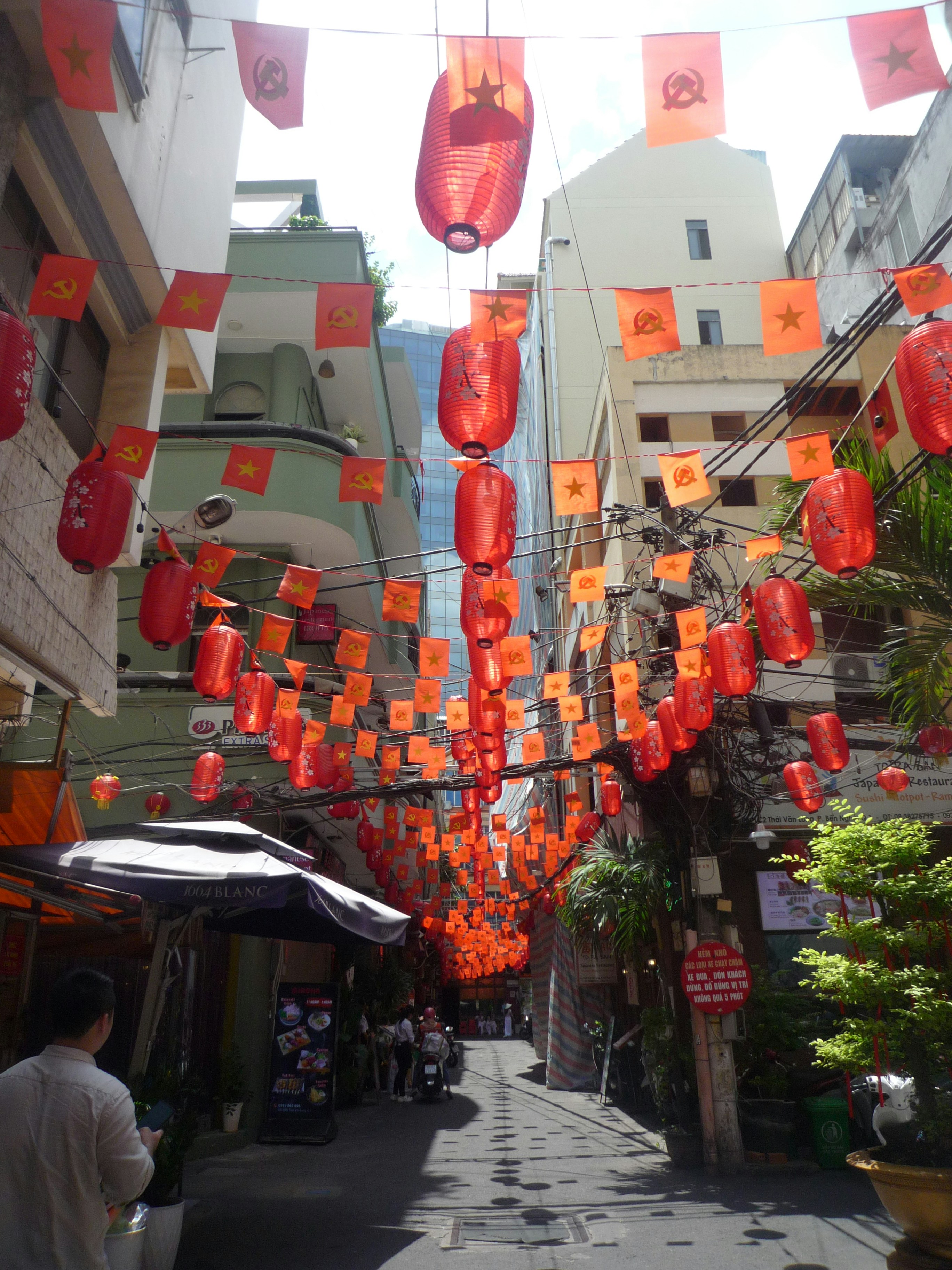 Lanterns and Flags Illuminate a Sunlit Alley Festival