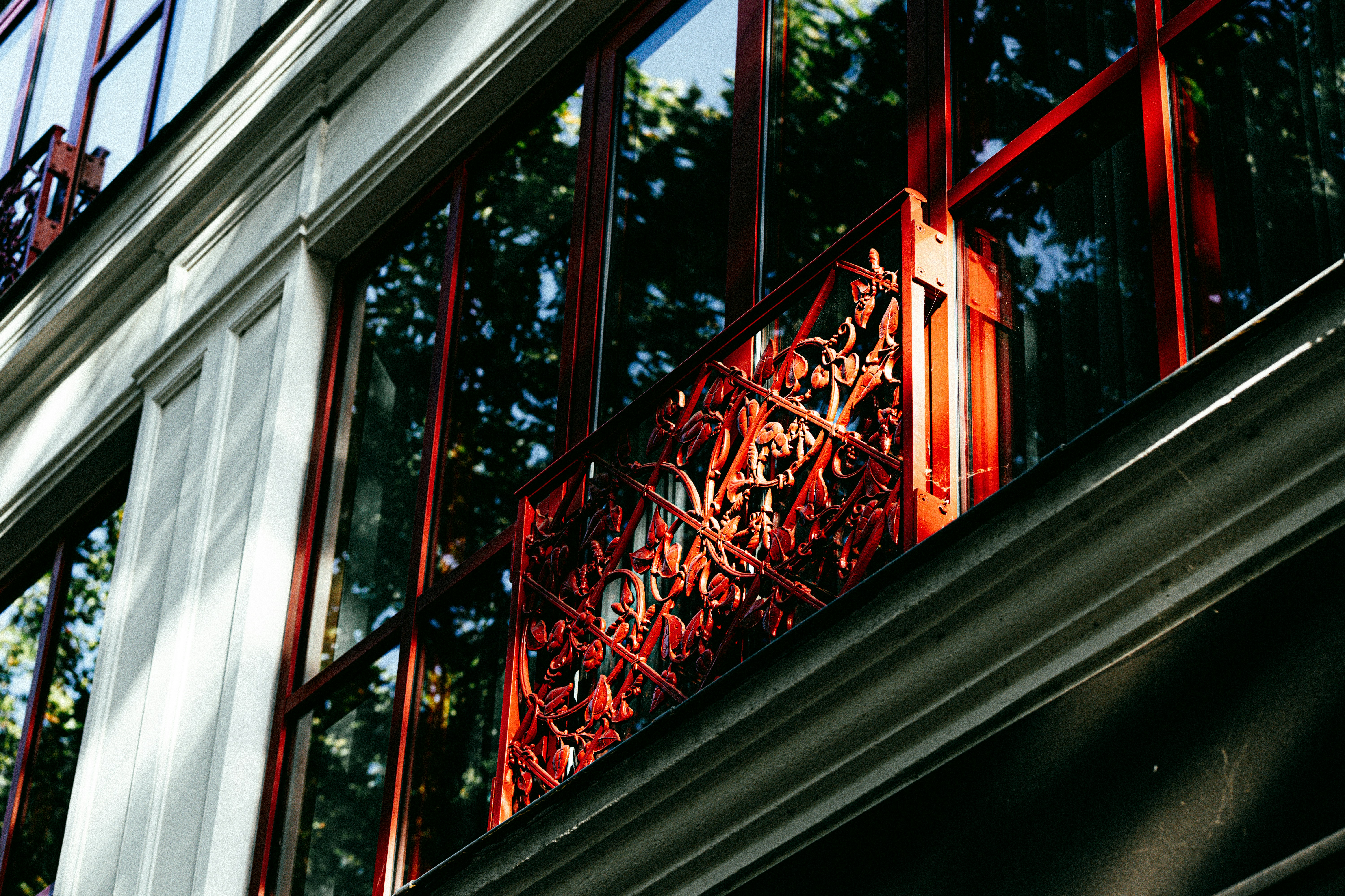 Red Ironwork Window: Sunlit Detail on a Modern Facade