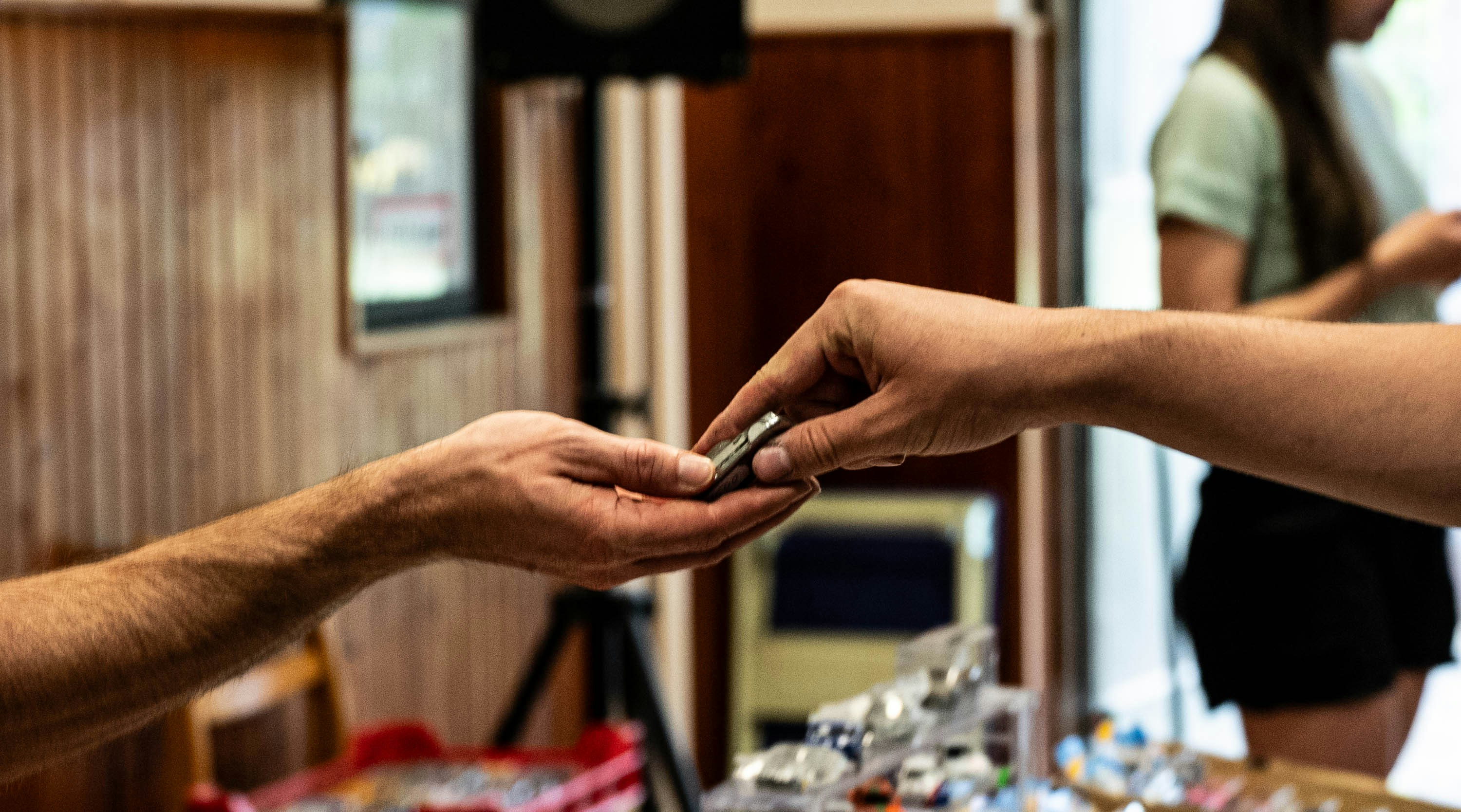 Hands exchanging a small metallic item.