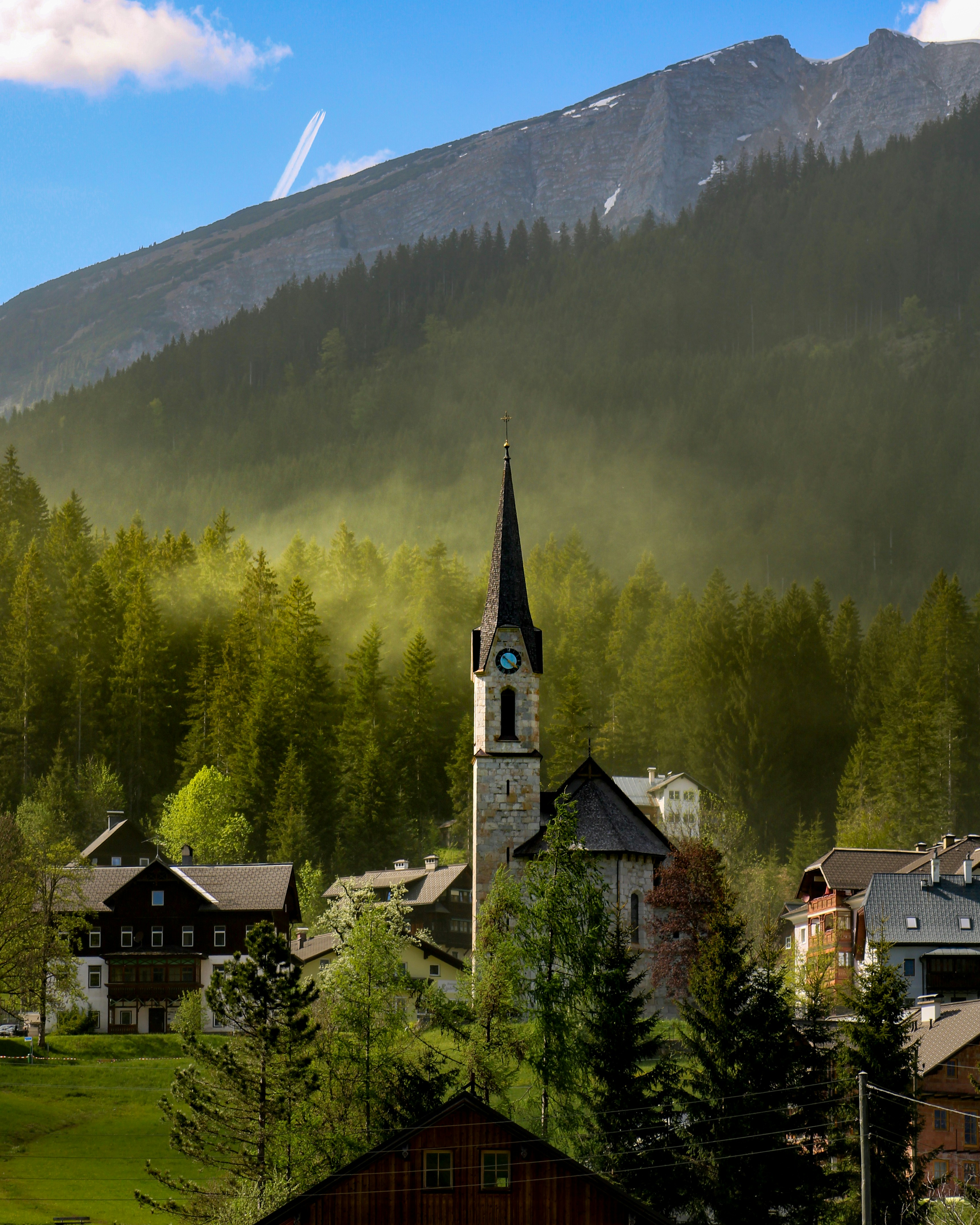 Village Church Rising Through Mist in Alpine Valley