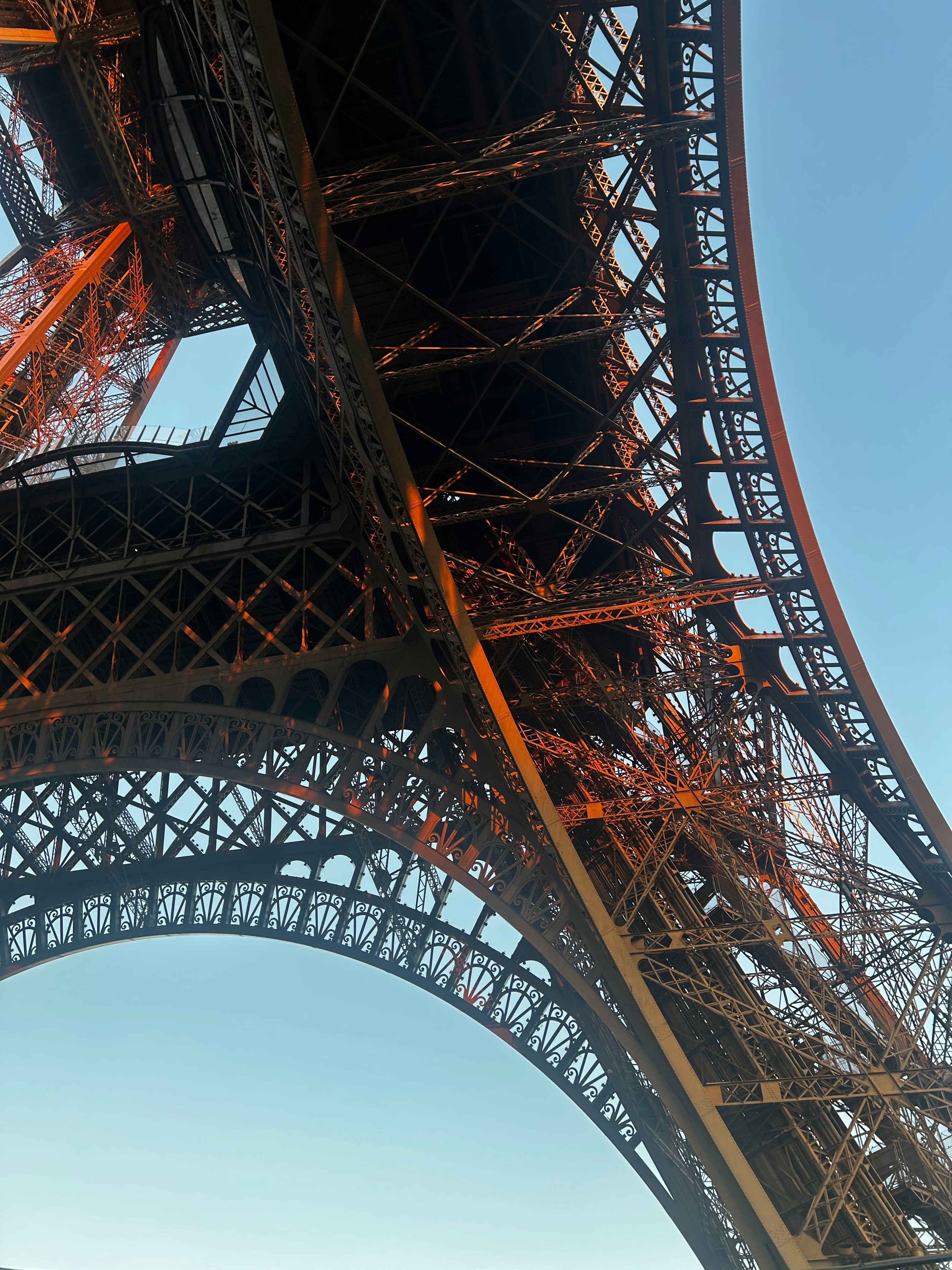 Eiffel tower structure against a clear blue sky at sunset.