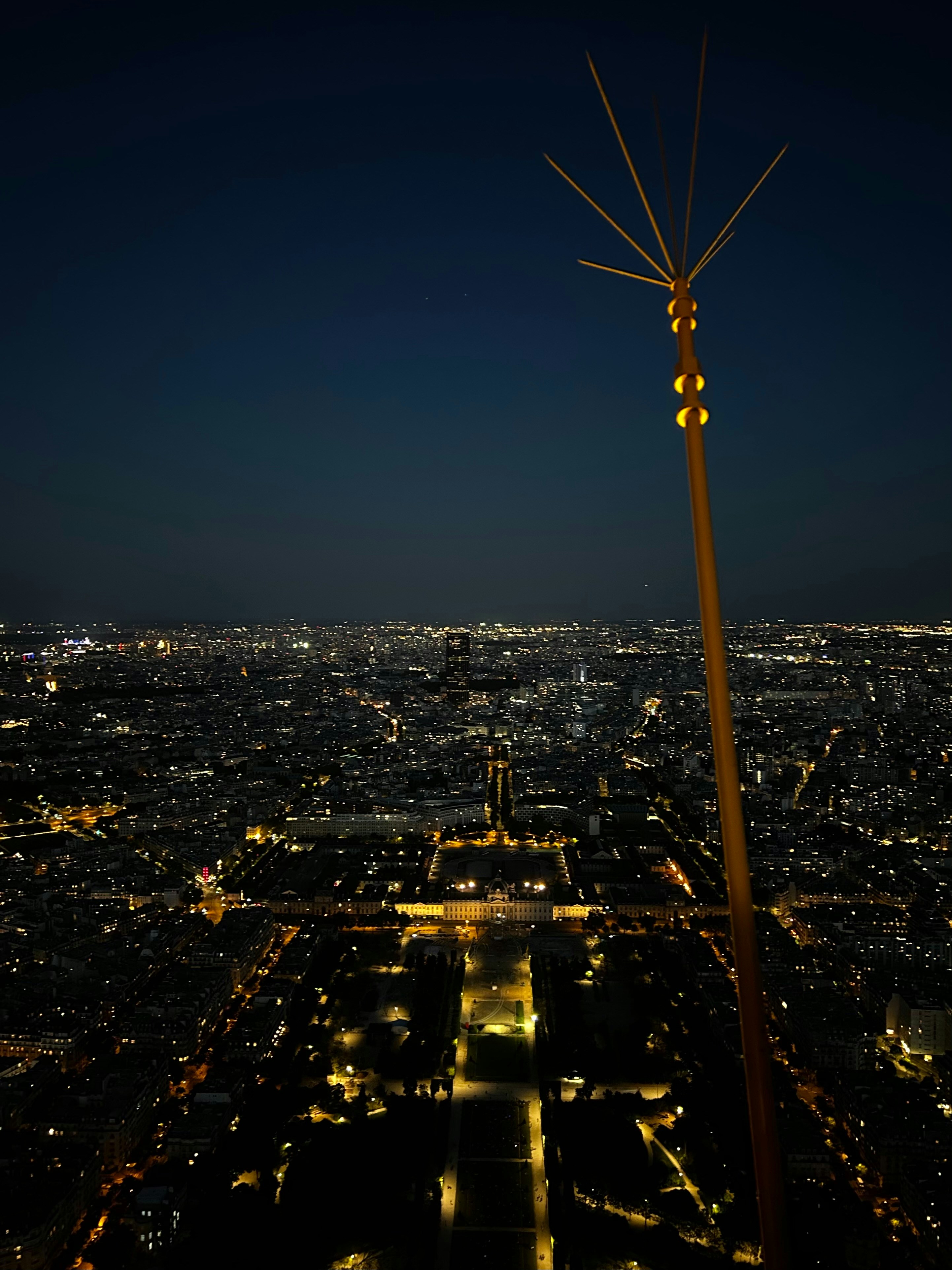 Illuminated spire overlooking a sprawling city at night.