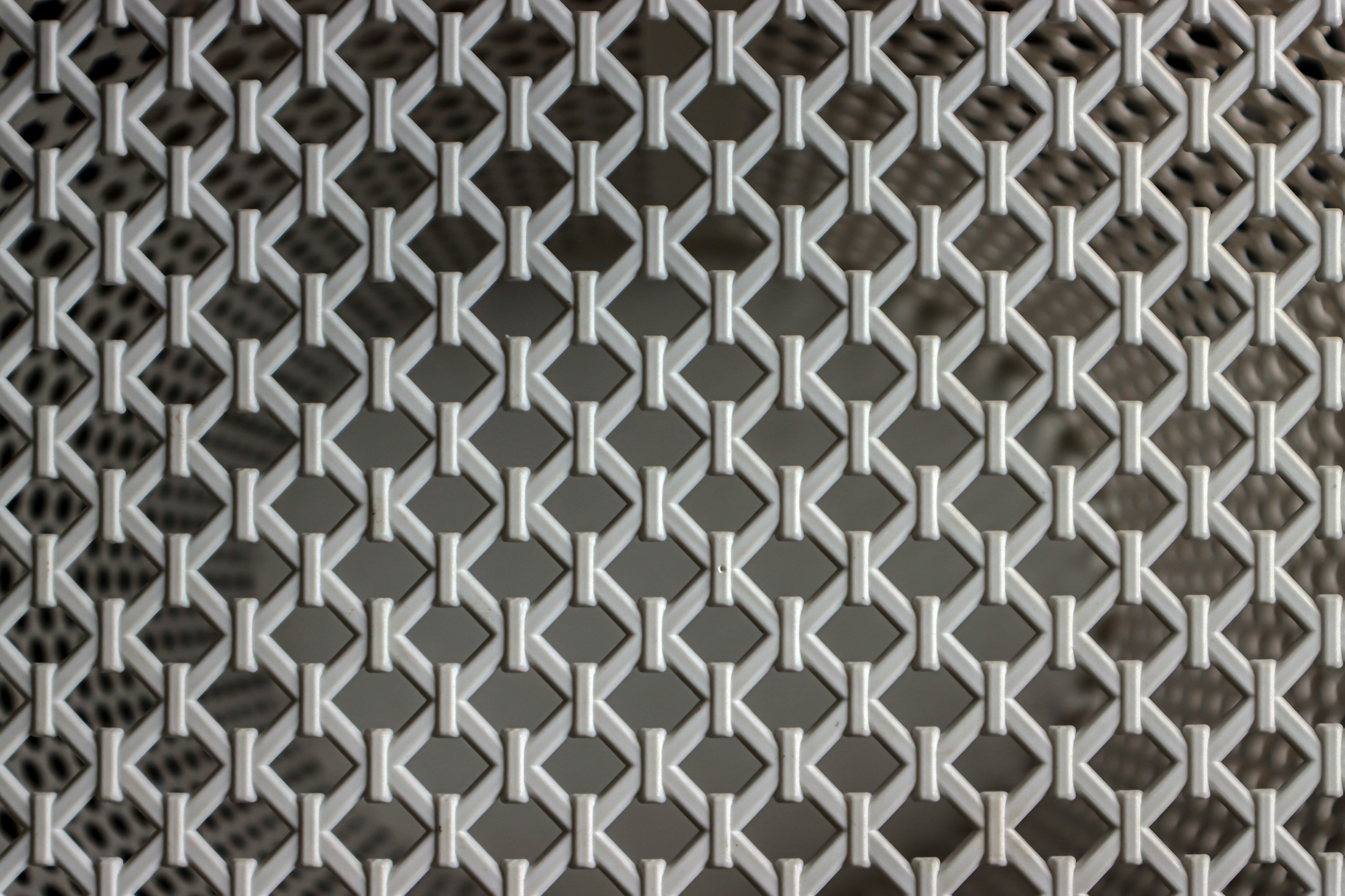 A white geometric mesh pattern on a dark background.