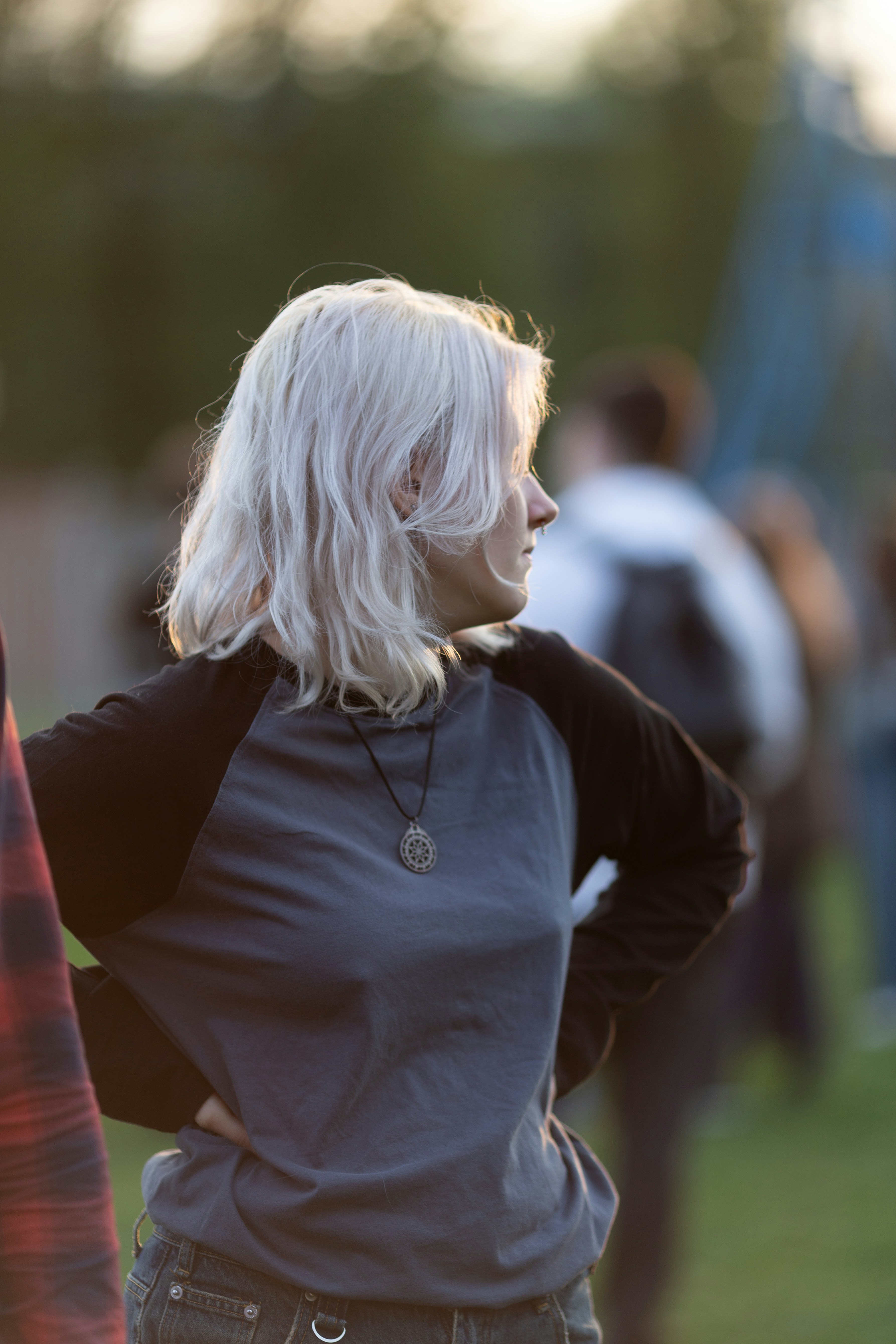 Portrait in soft backlight: a silver-haired subject pauses in a sunlit gathering