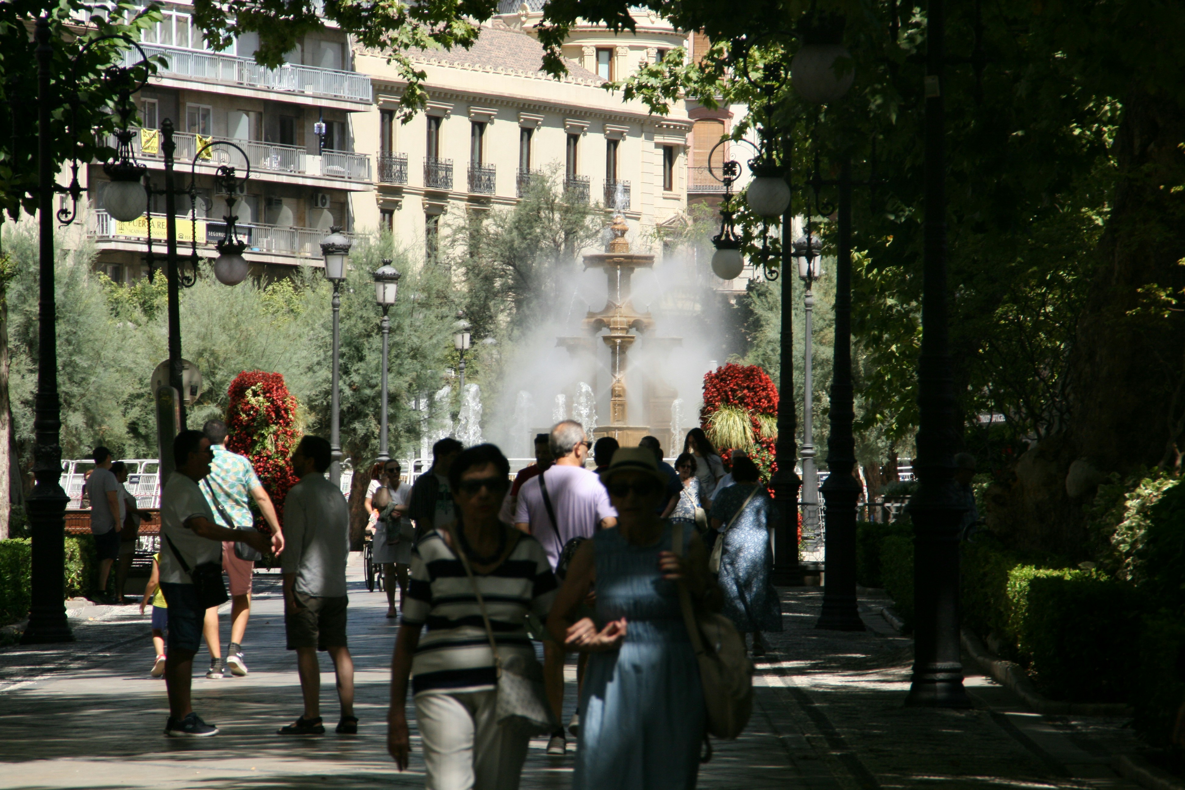 Midday in the Fountain Lane: People Wander Toward the Mist