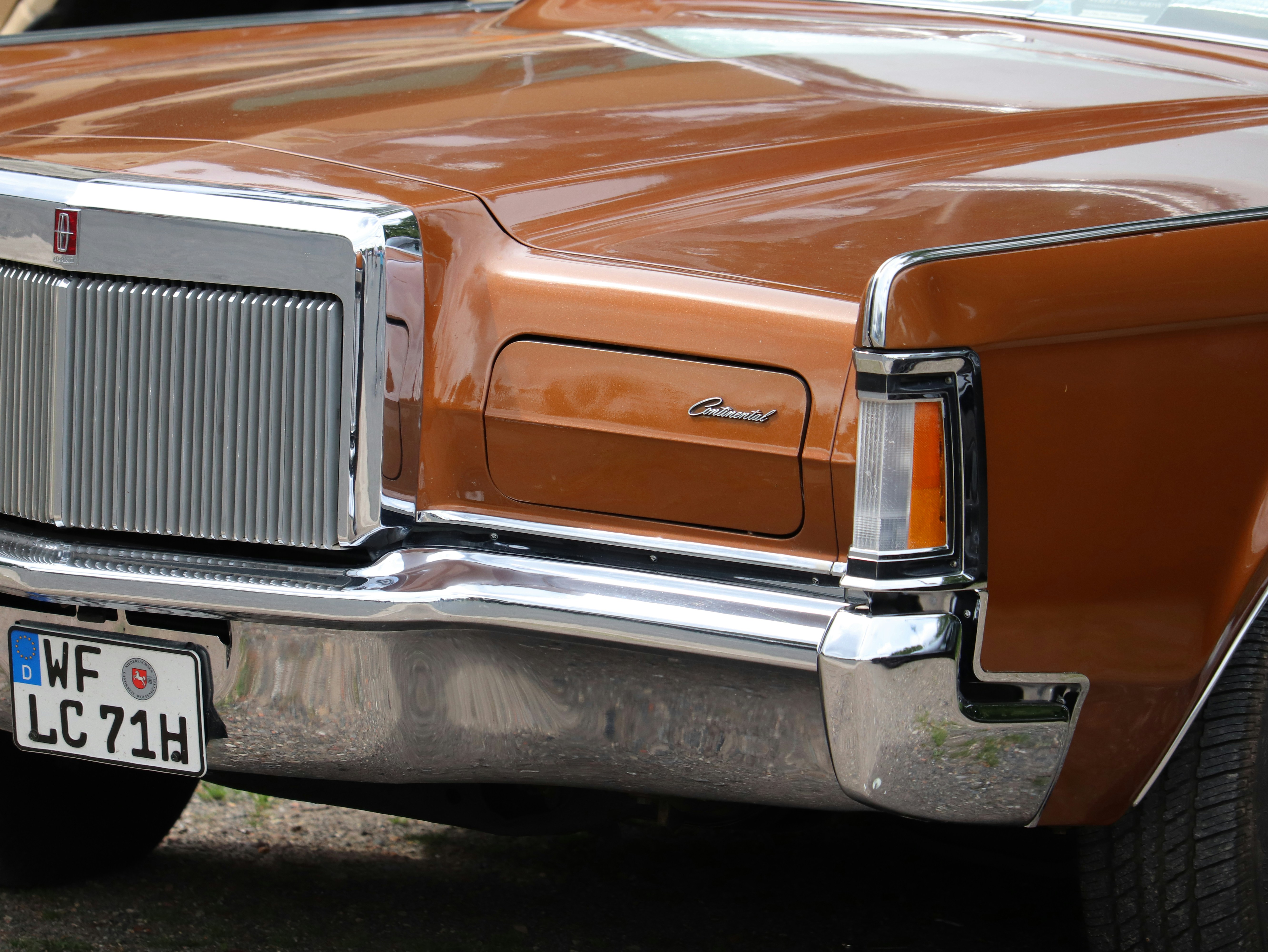 Chrome Grille and Burnished Orange: A Classic Car’s Front Corner