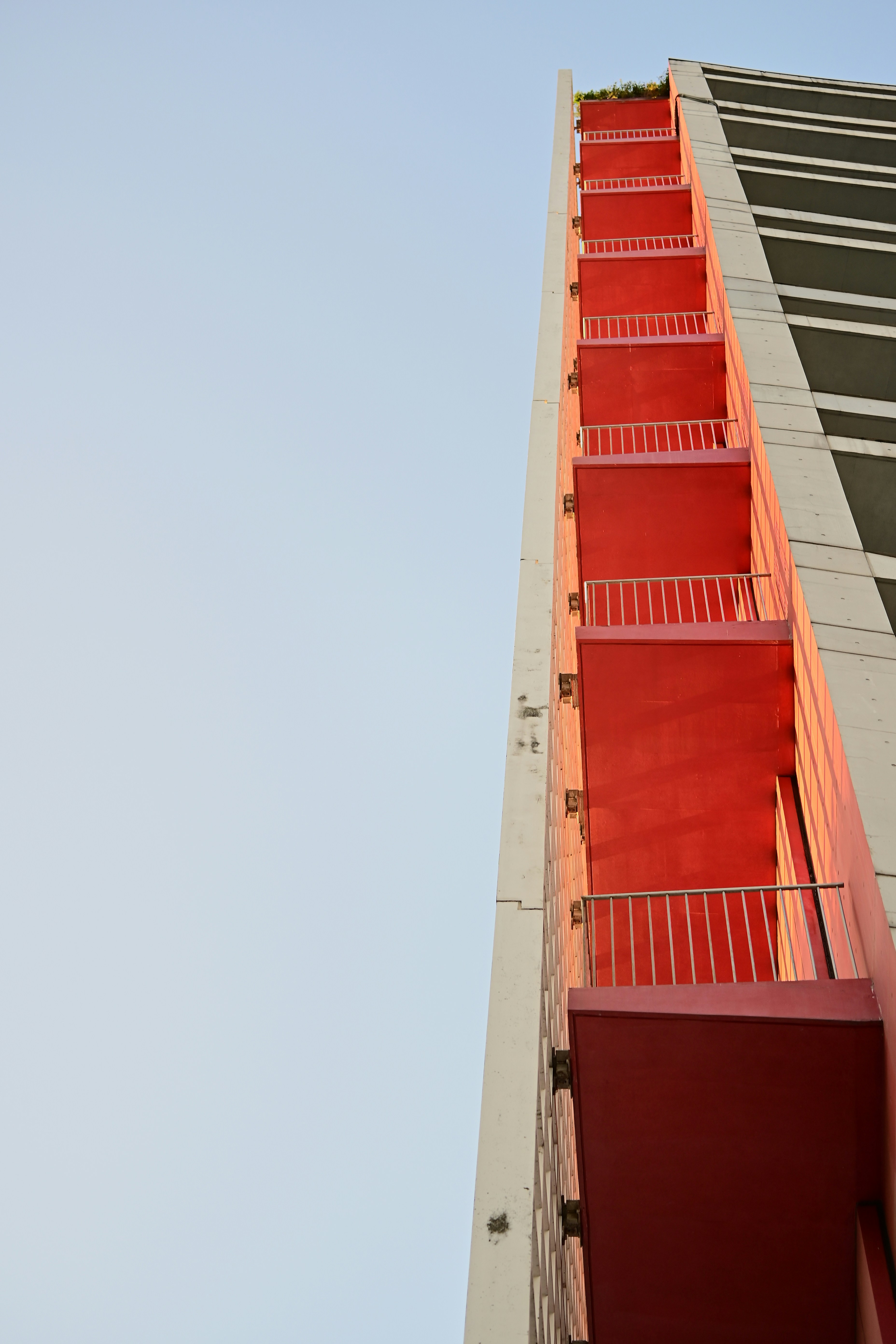 Bold Red Balconies Ascend the Concrete Facade