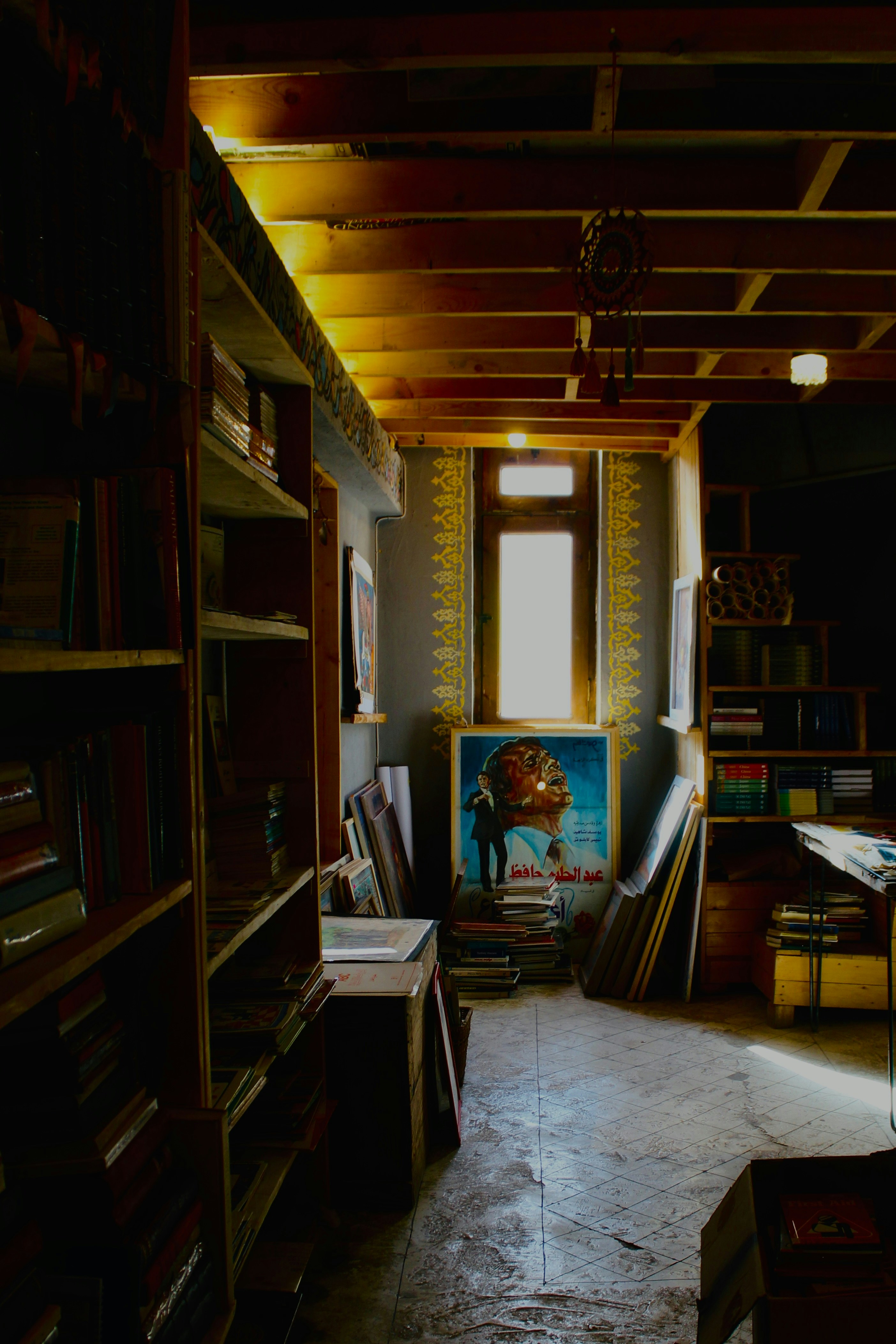 Rustic room with bookshelves, exposed beams, and a bright window.