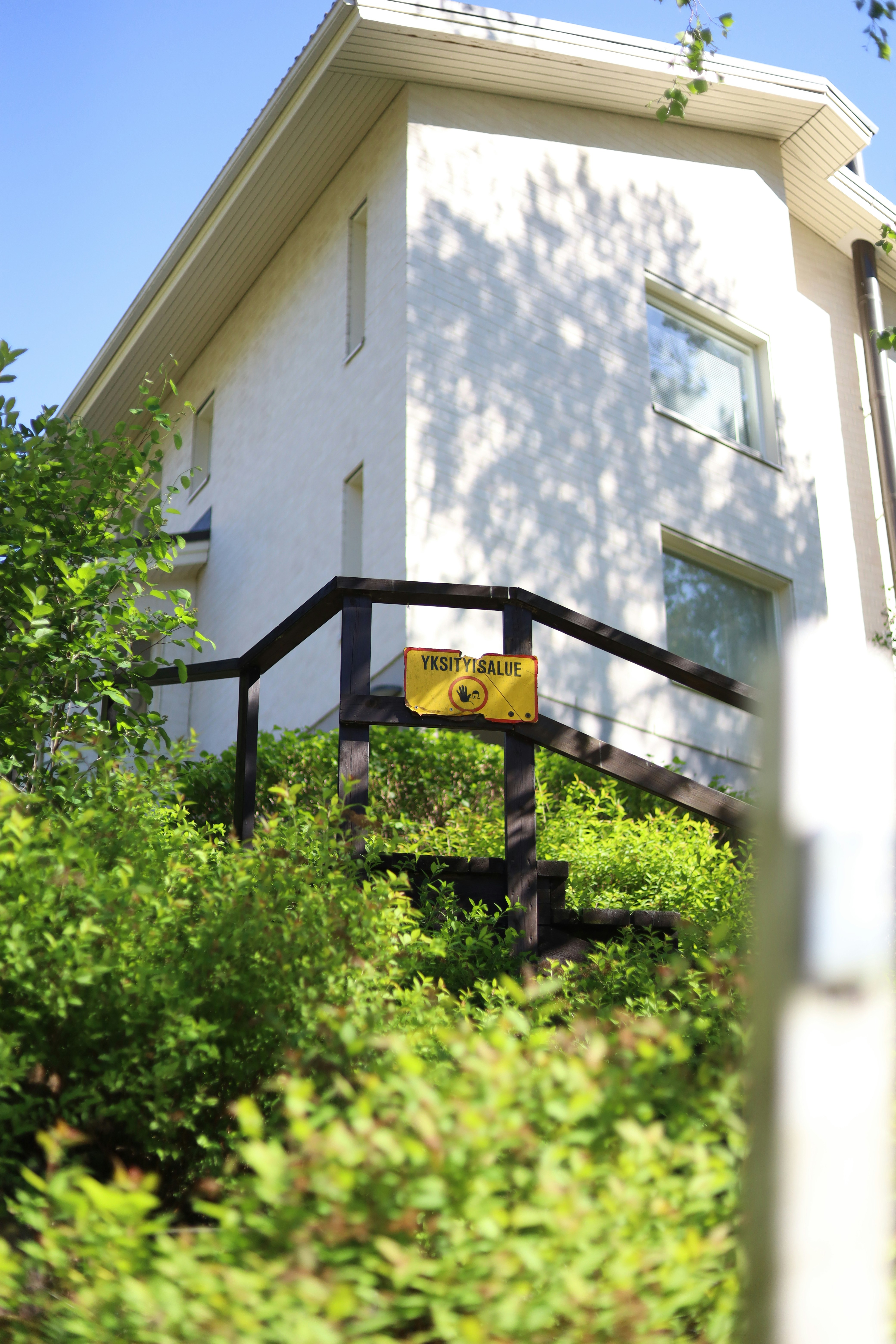 Sunlit House Gate: Hidden Sign Amid Greenery