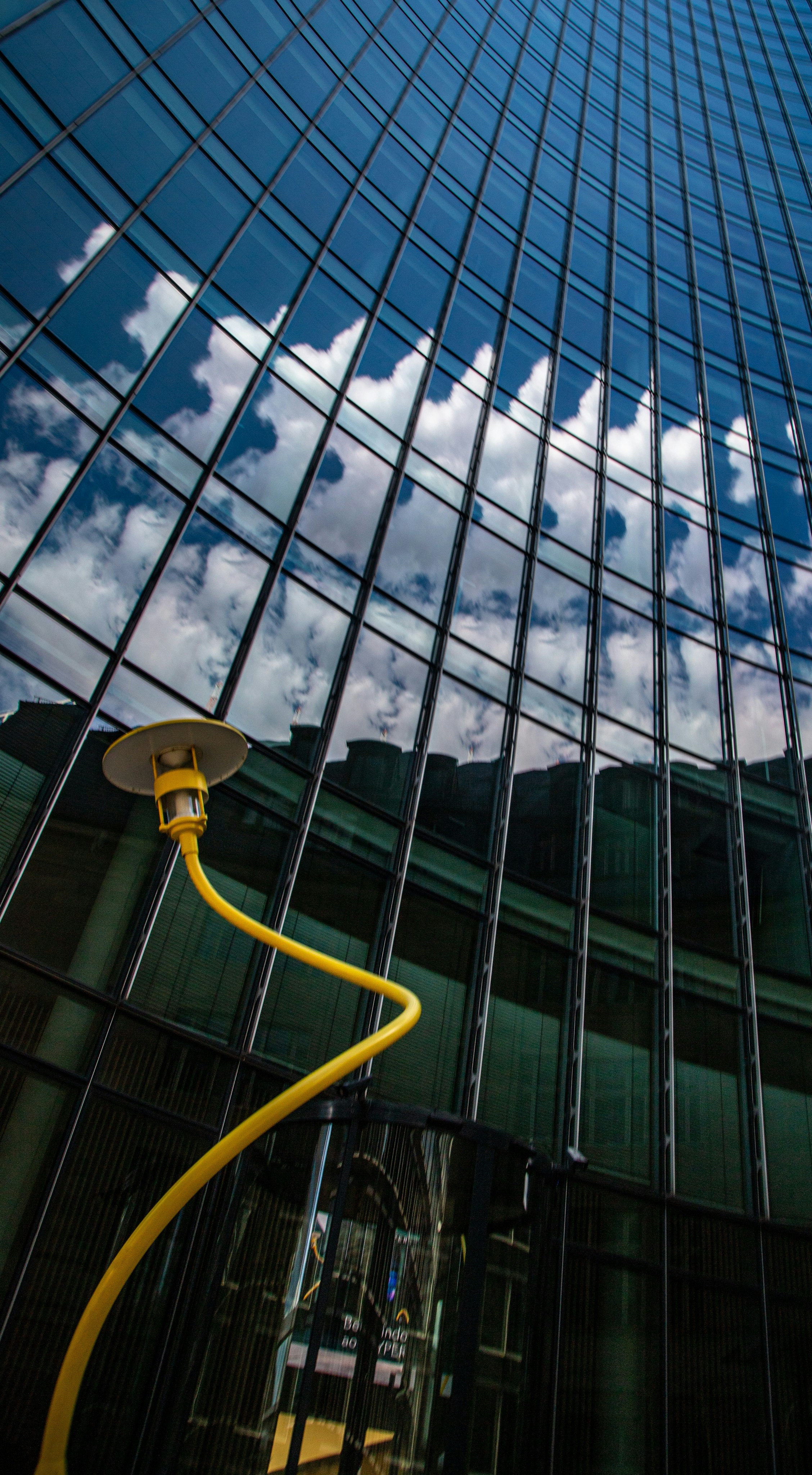Curved Electro-sky: Yellow Cable in Front of Glass Skyscraper