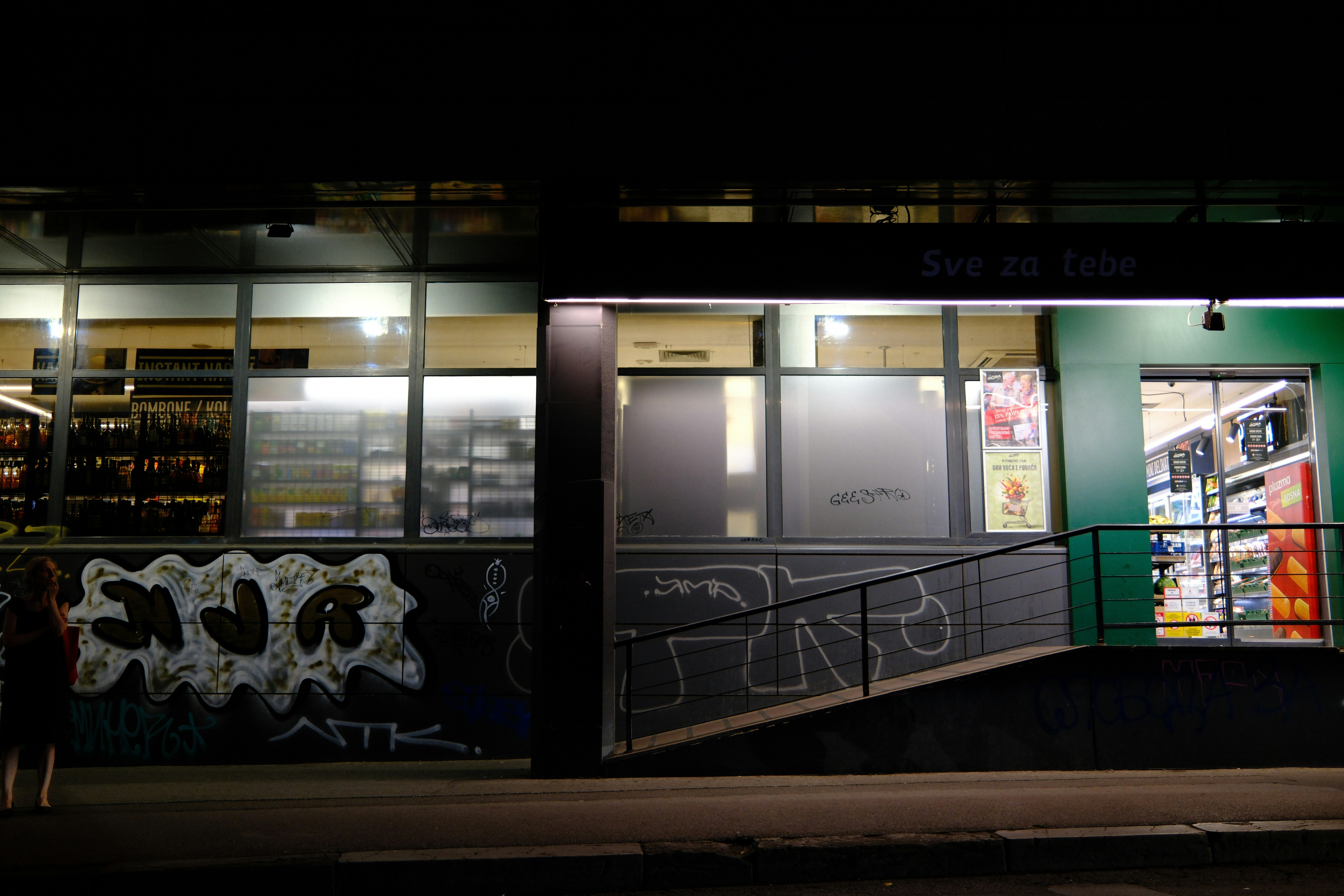 Nighttime view of a store with illuminated windows and graffiti.