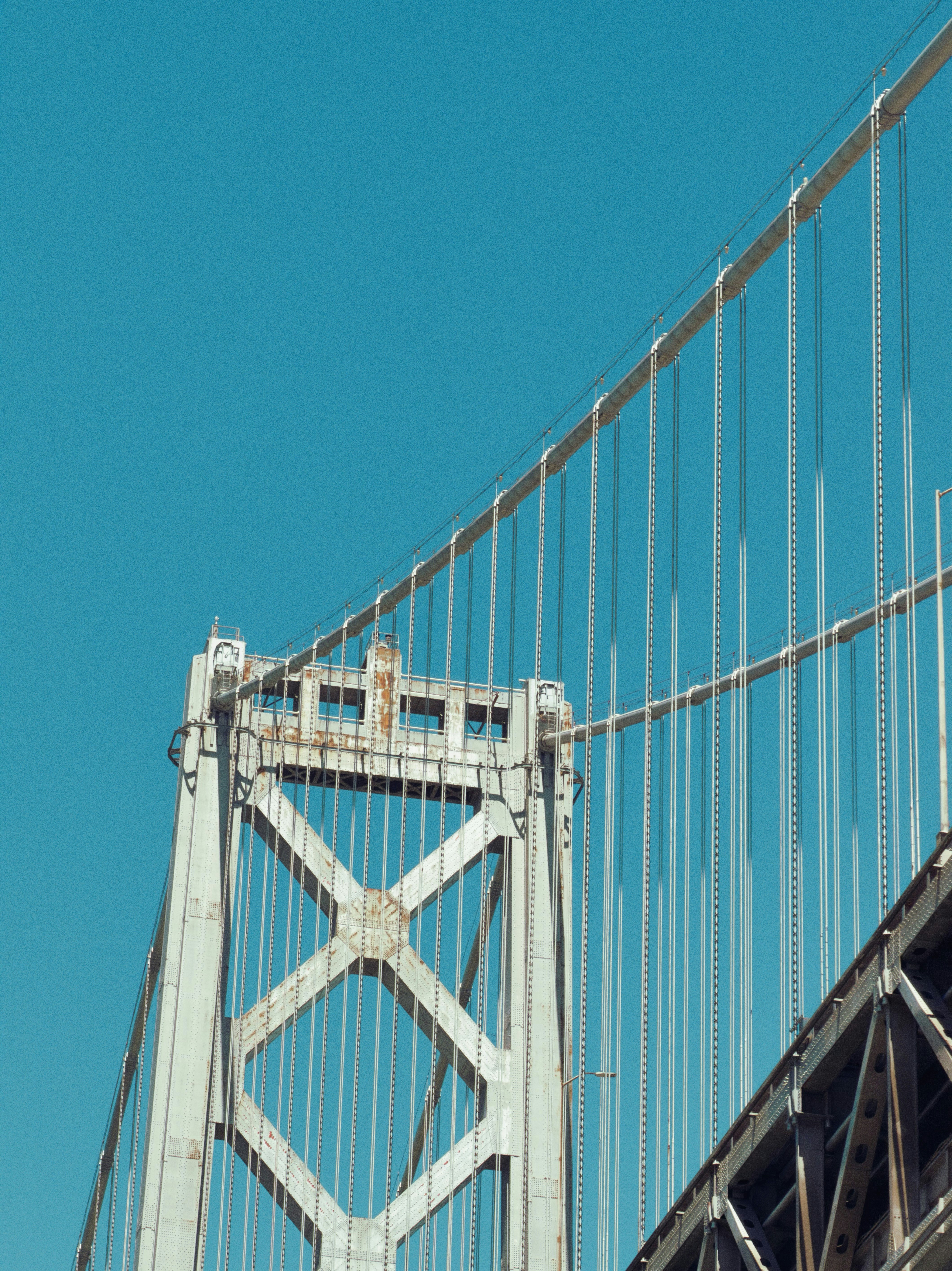 A bridge tower and suspension cables against a blue sky.