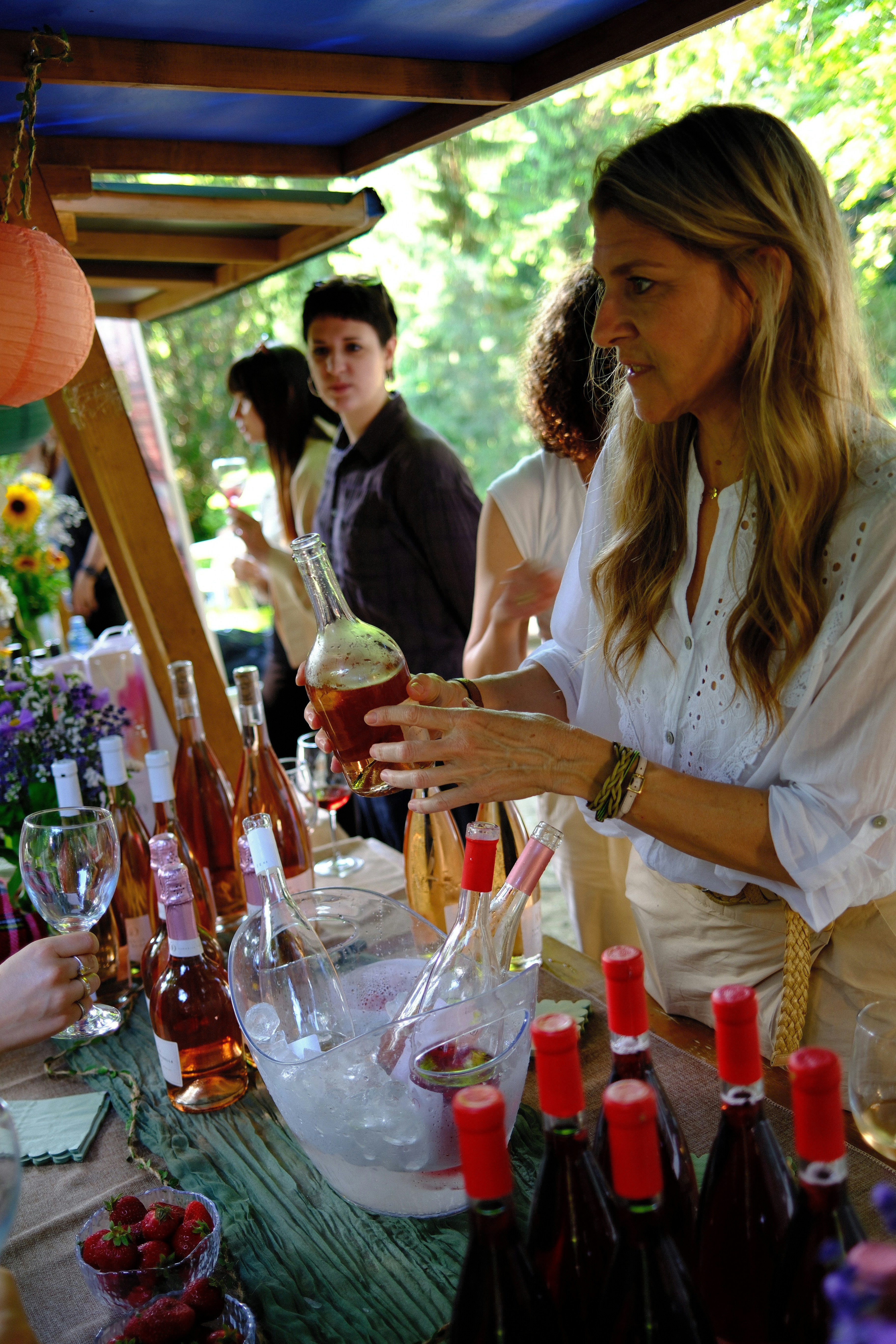 Graceful Pour: A woman pours rosé at a sunlit outdoor tasting