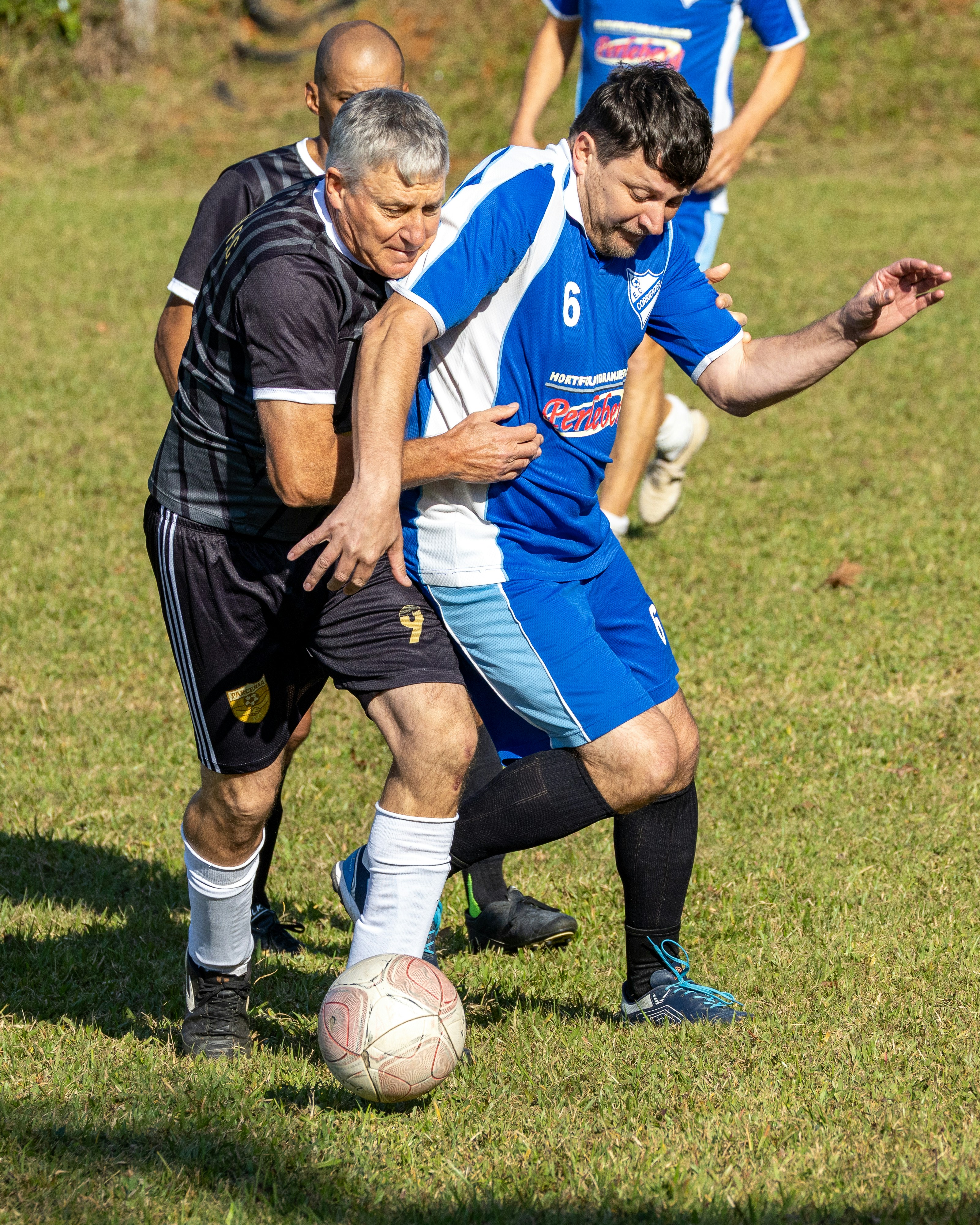 Midfield Scramble: Striker in Blue Battles for Ball under Grass Field