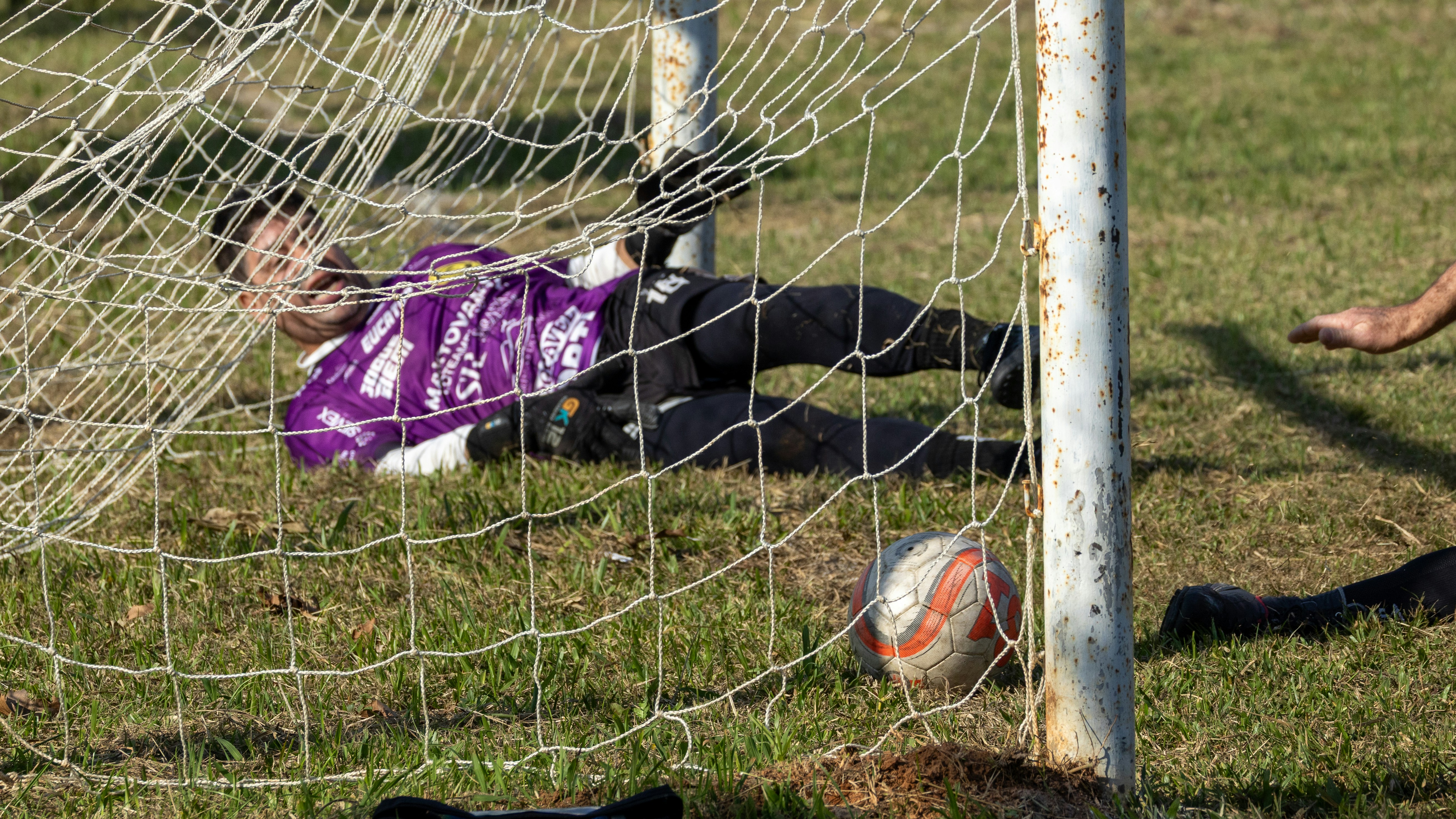 Purple-clad goalkeeper mid-dive to deny a close-range strike