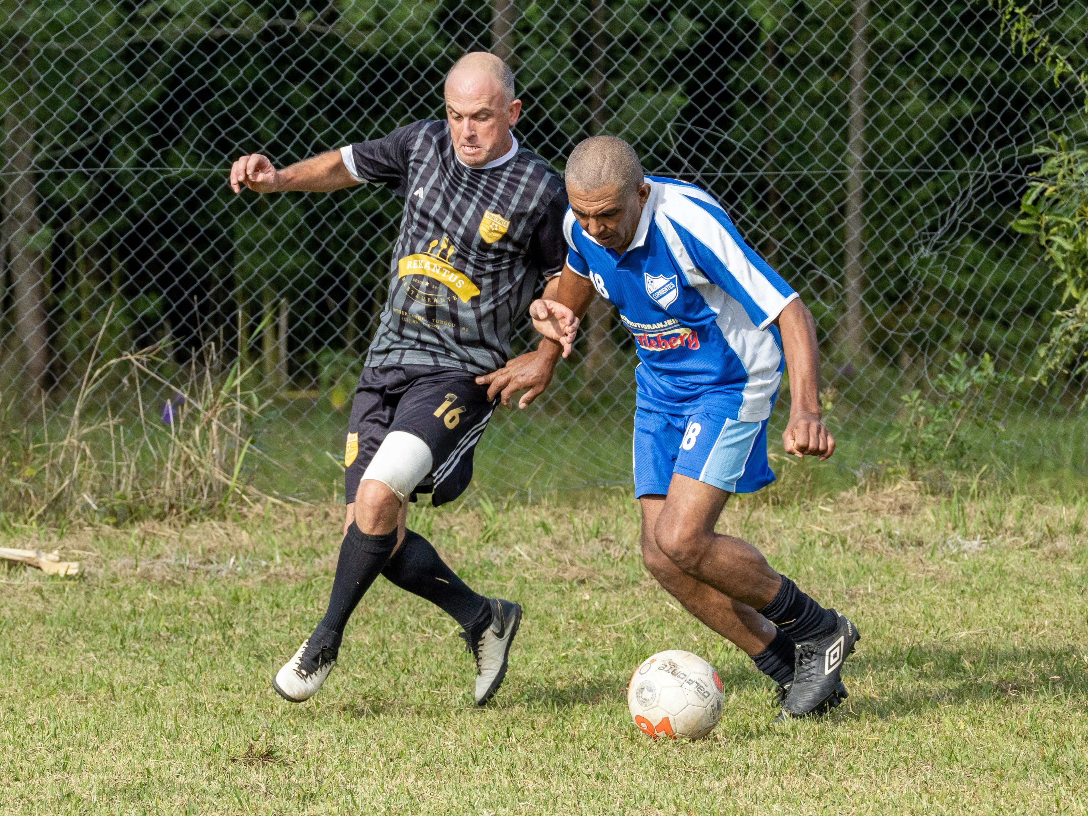Two men playing soccer on a grassy field.