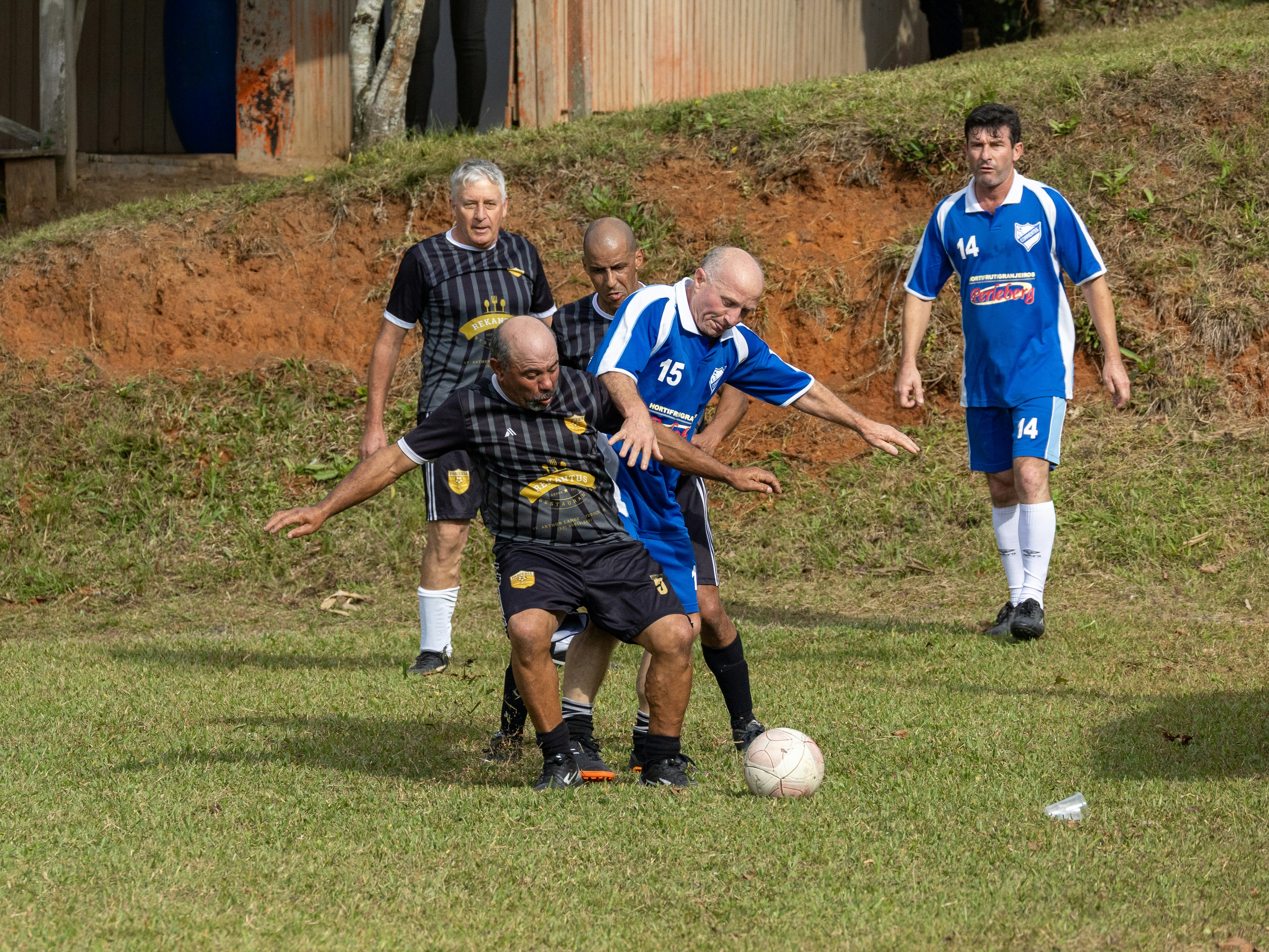 Adult men playing soccer on a green field.
