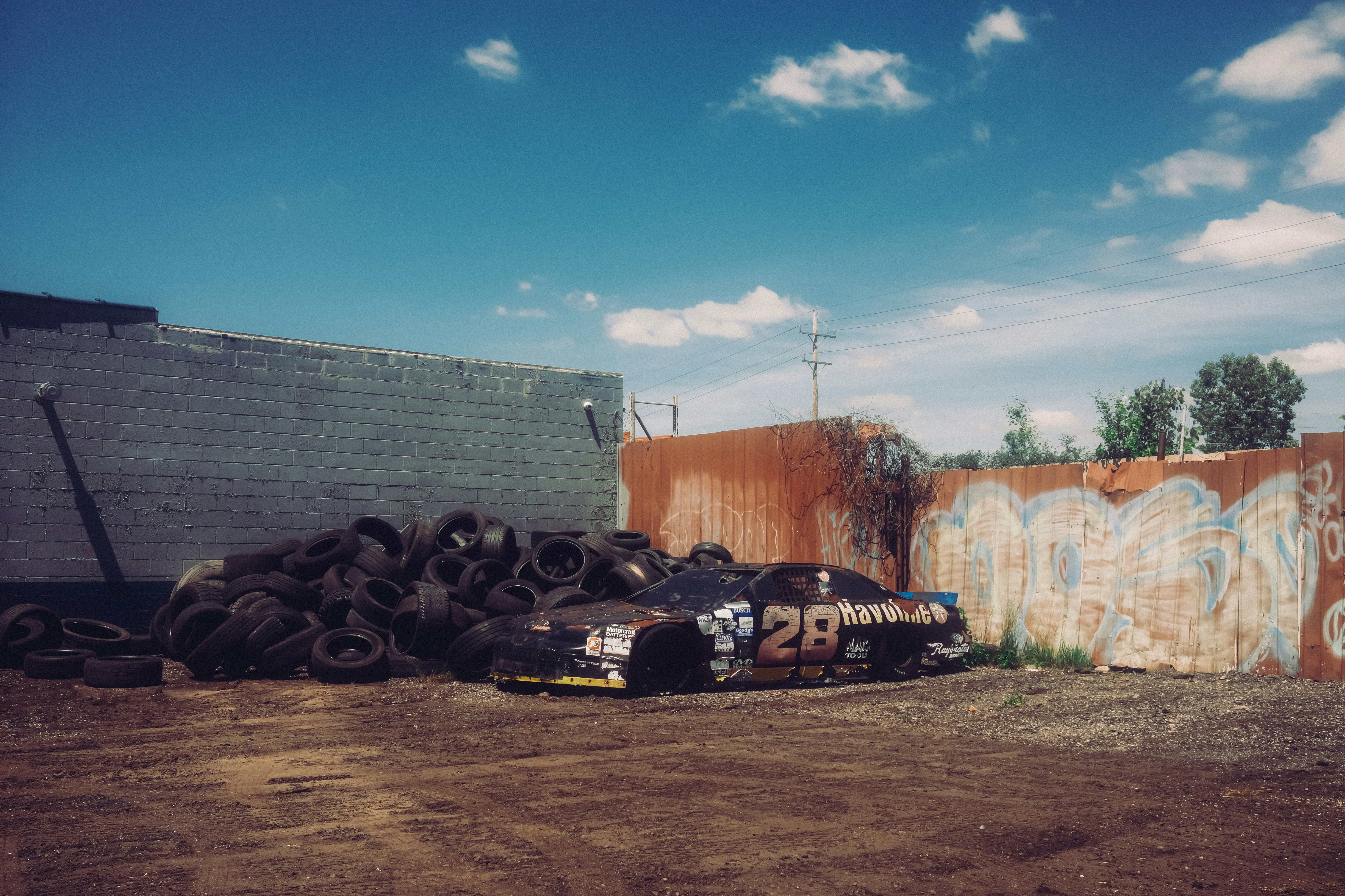 Dilapidated race car and old tires in a dusty junkyard.