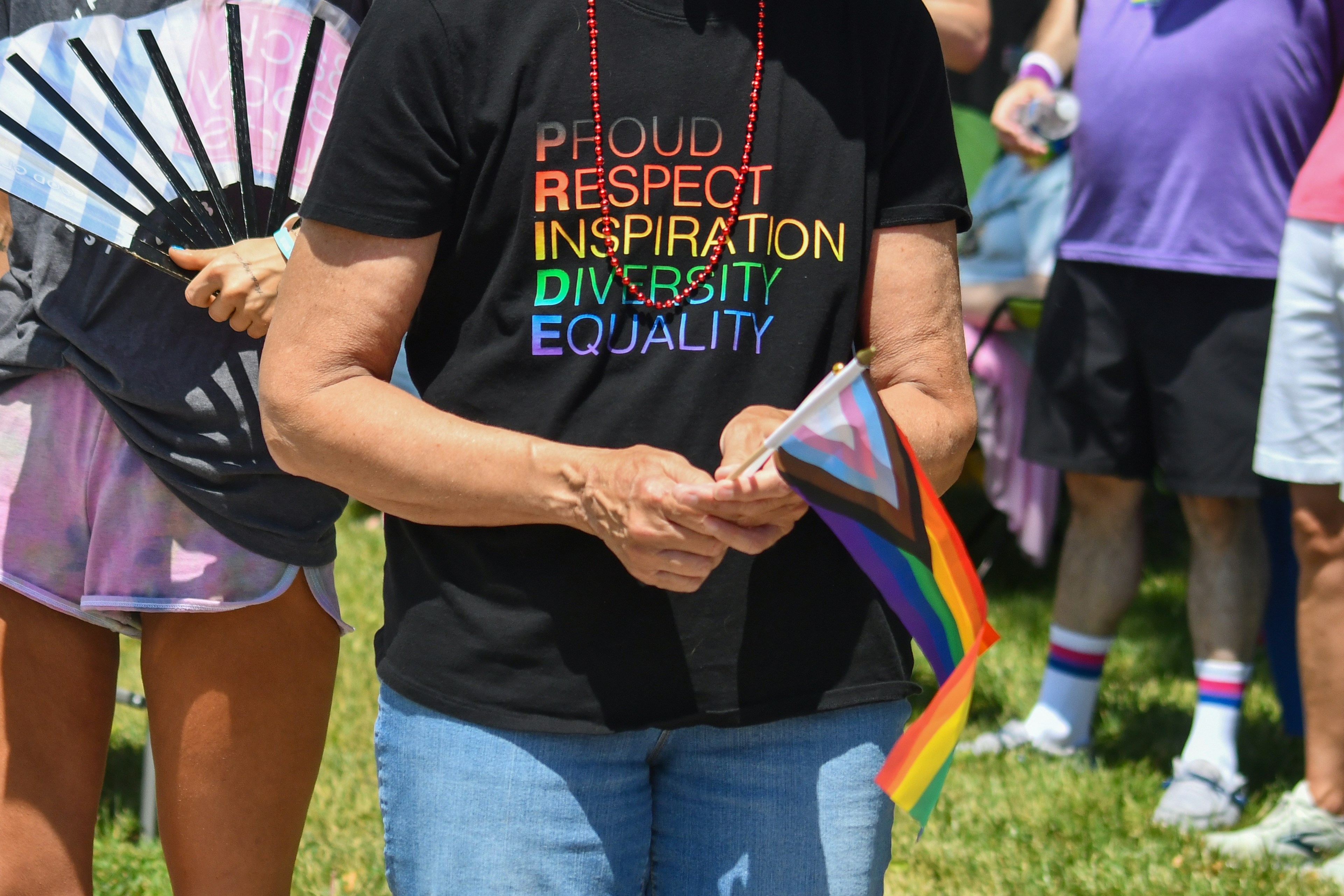 Rainbow Threads: Pride Shirt and Handheld Fan at a Pride Event