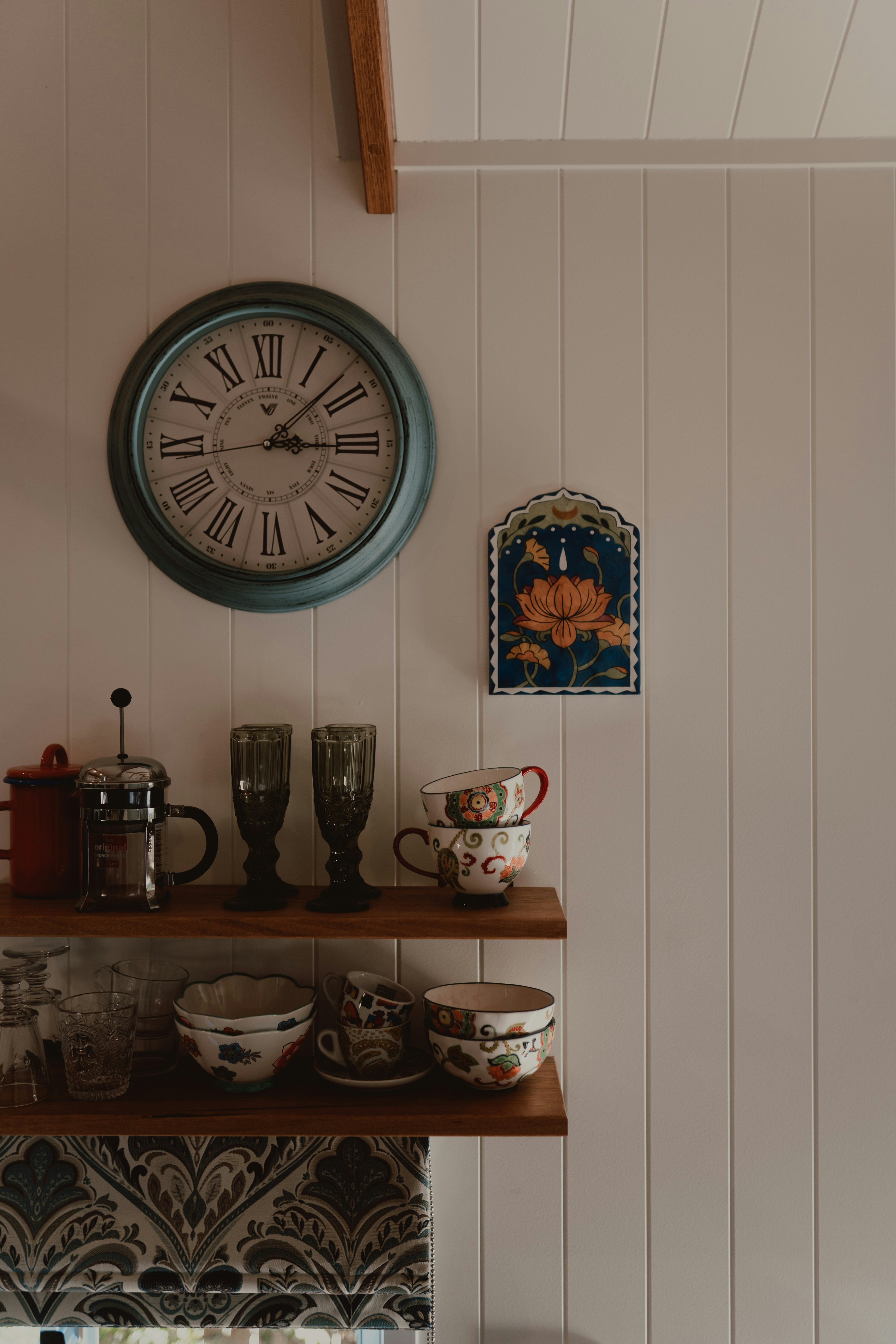 A wall with a clock, decorative tile, shelves, and kitchenware. photo ...