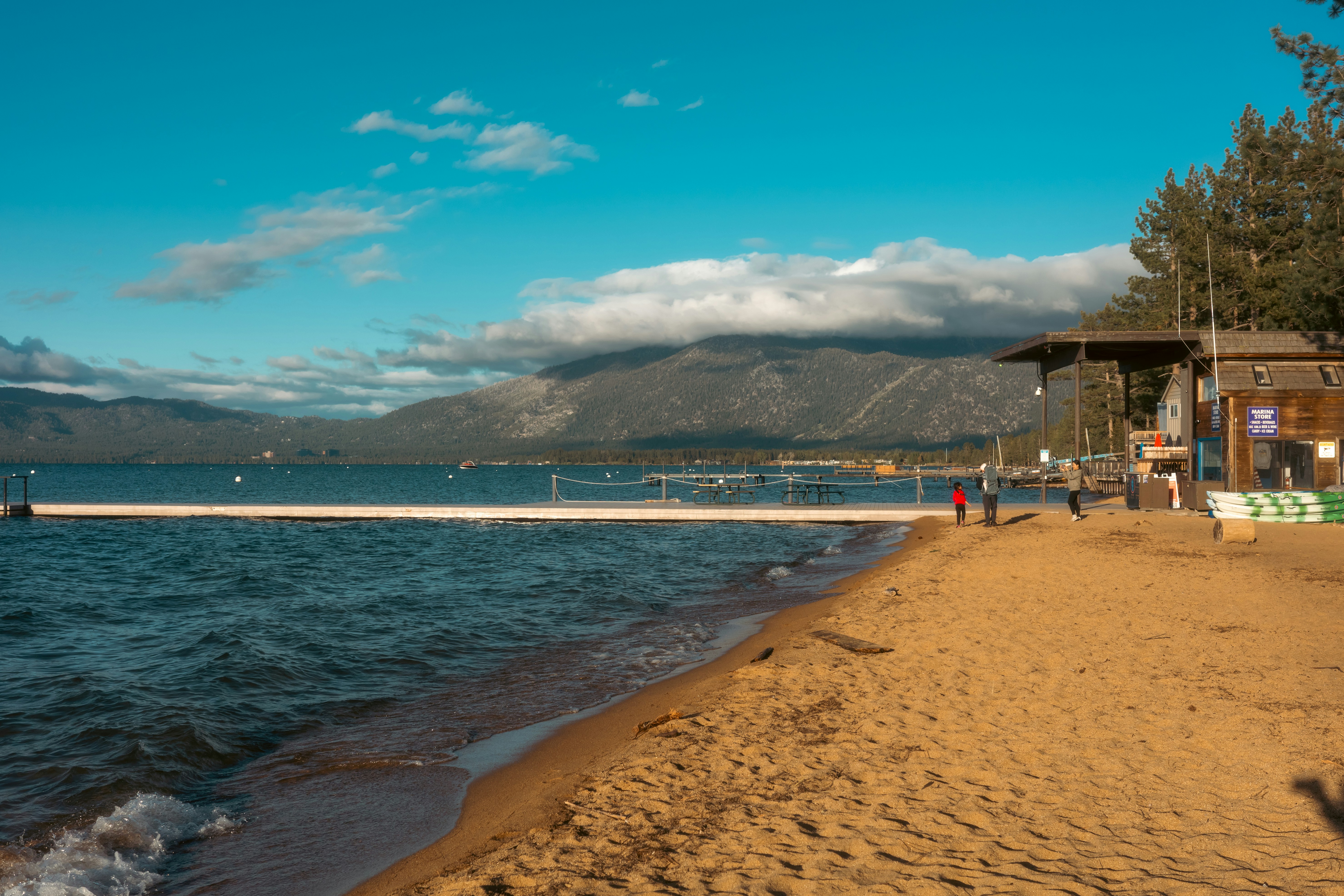 Sunlit Beachfront with Distant Peaks and Marina Activity