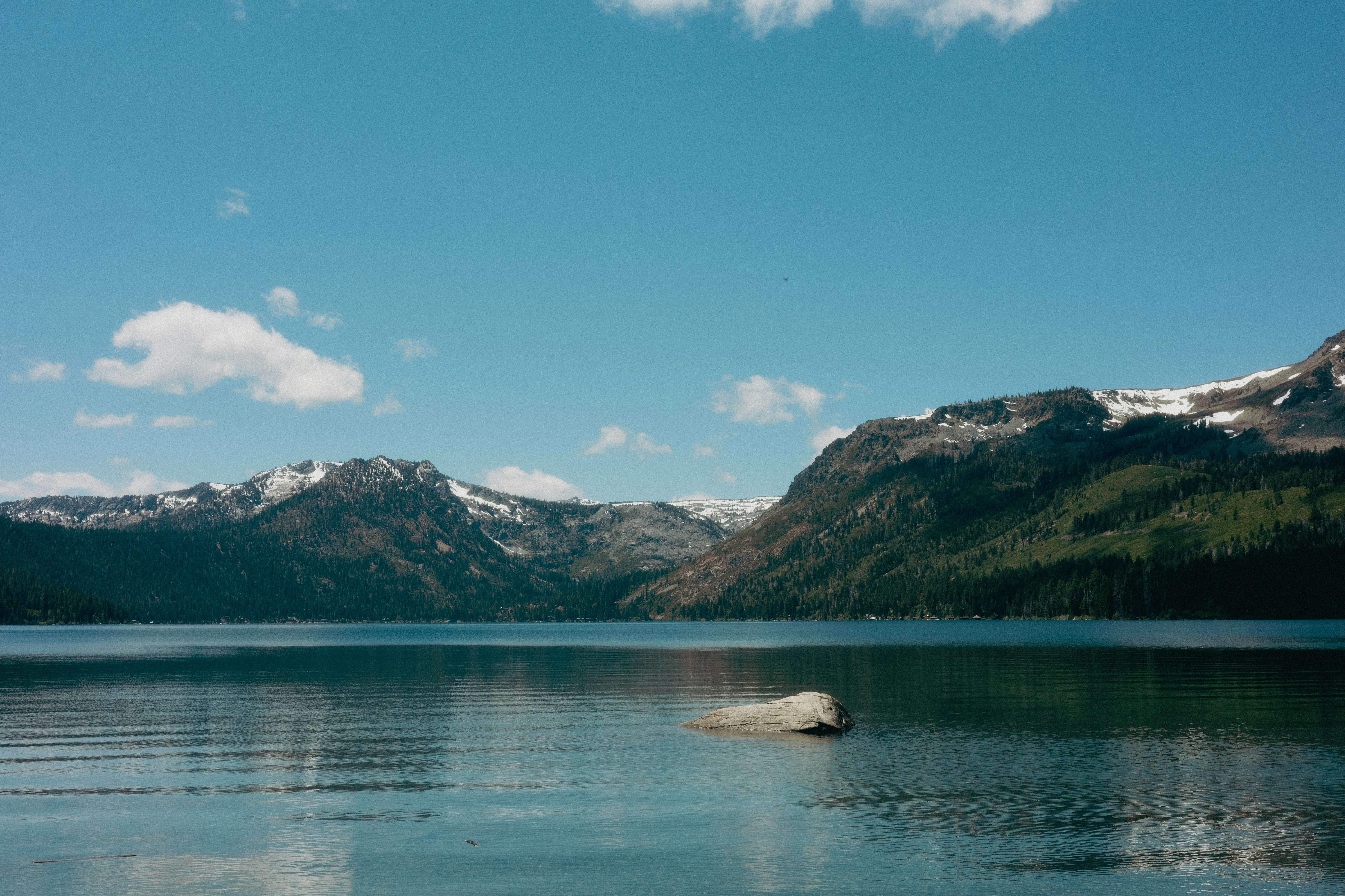 Glacial Lake Quietude: A Lone Boulder Cradled by Mountain Mirrors