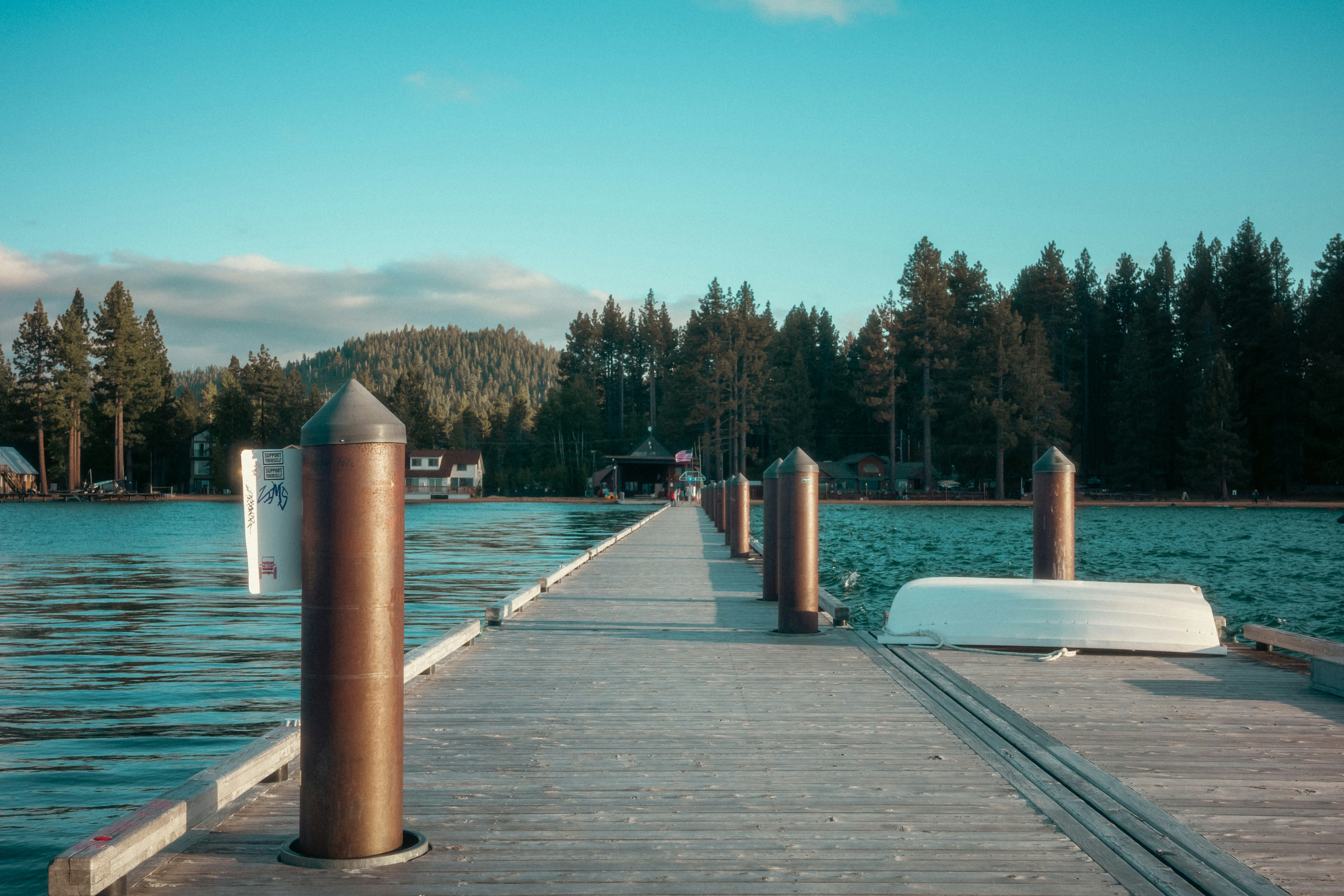 Wooden pier on a calm lake with distant pine trees.