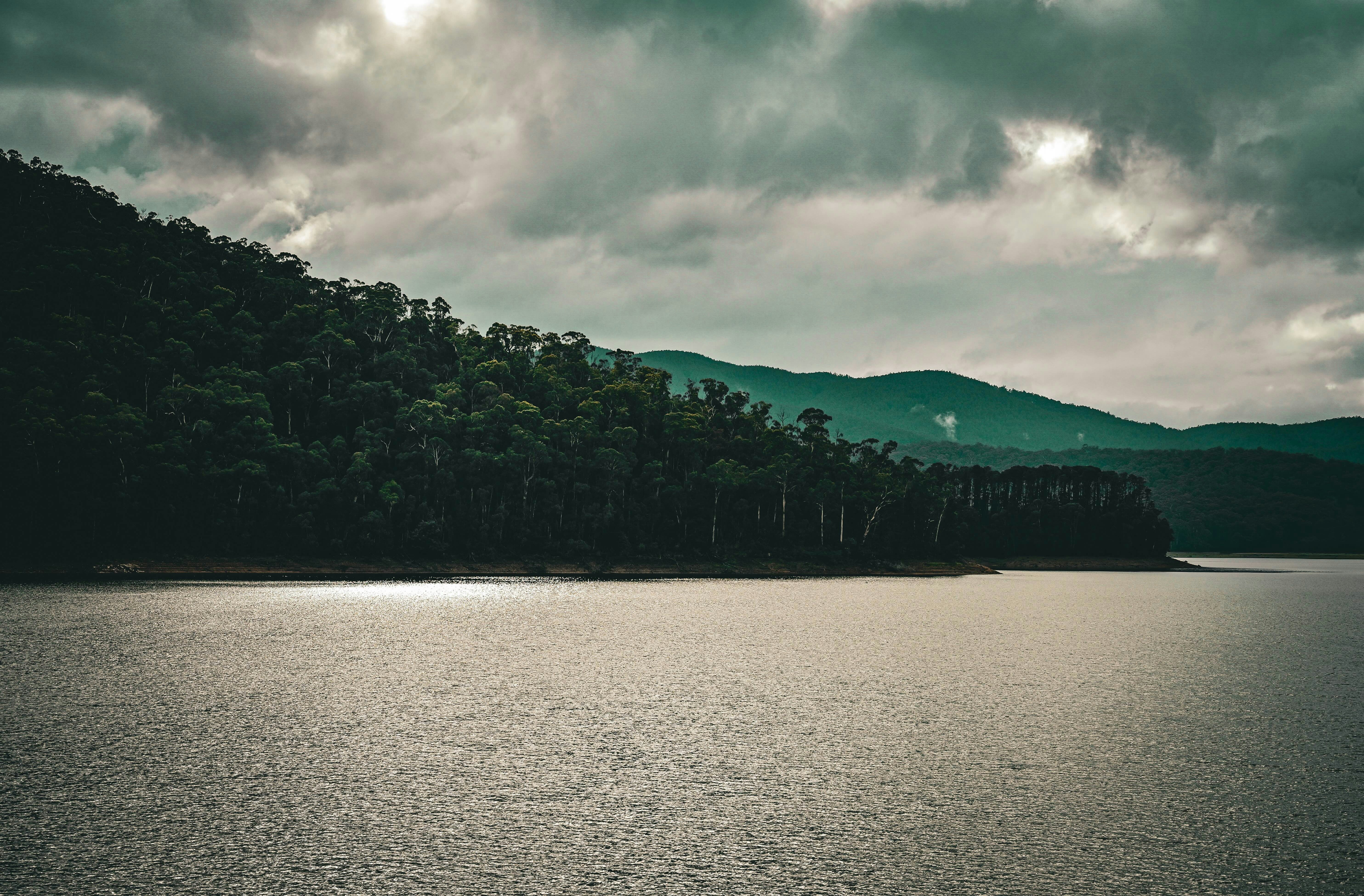 Dark clouds over a tranquil lake and dense forest.