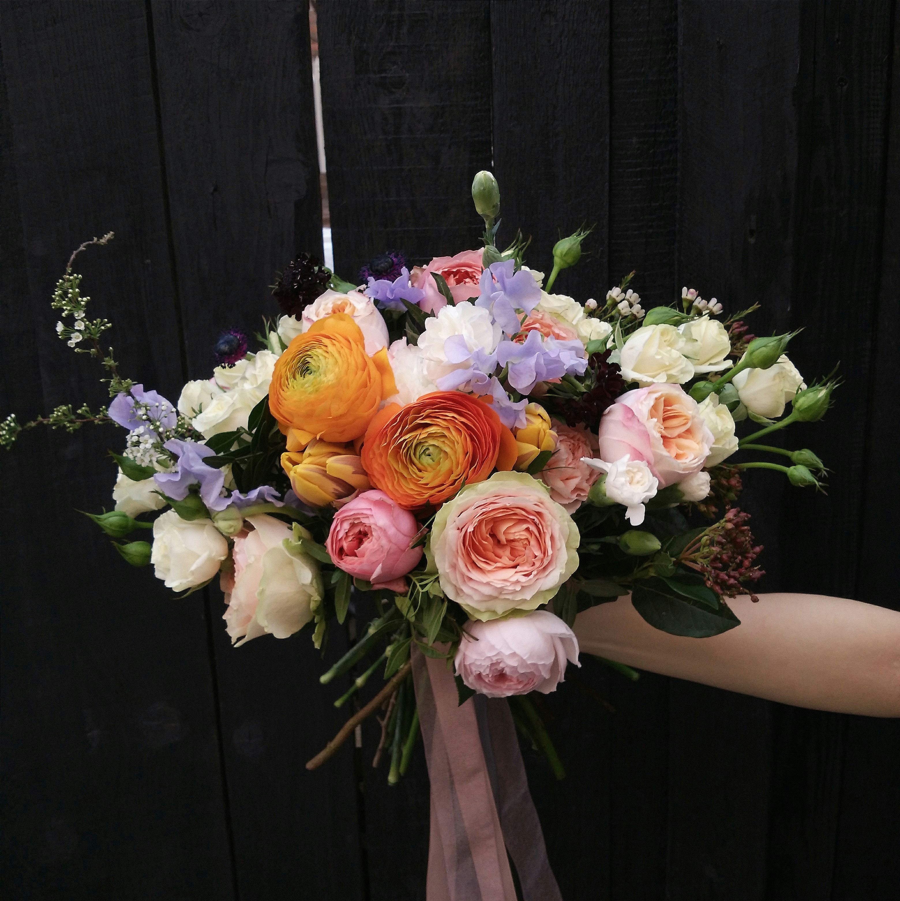 Bouquet of Sunset Peonies in Hand with Dark Fence Backdrop