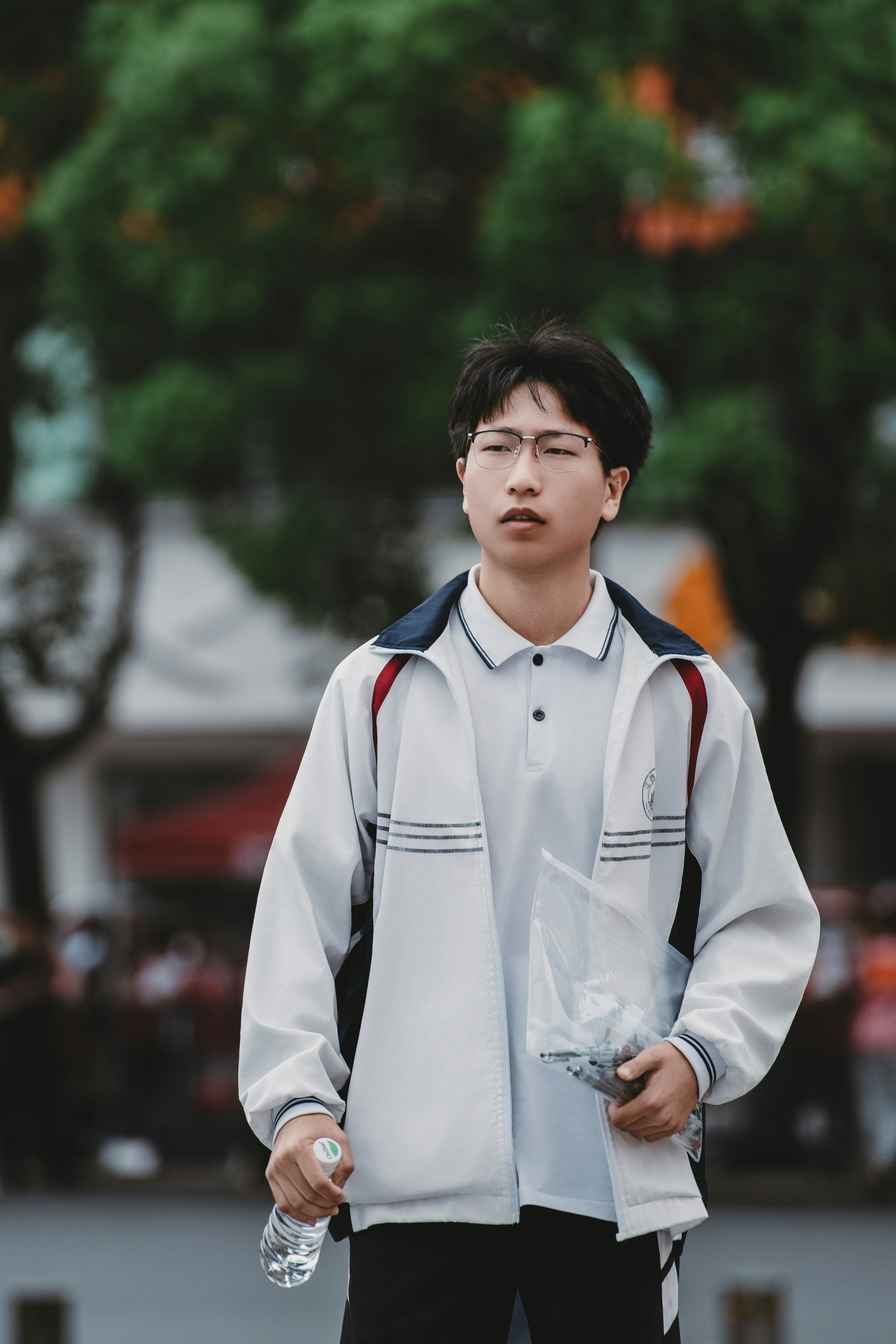 Student in a white jacket with backpack and water bottle on campus