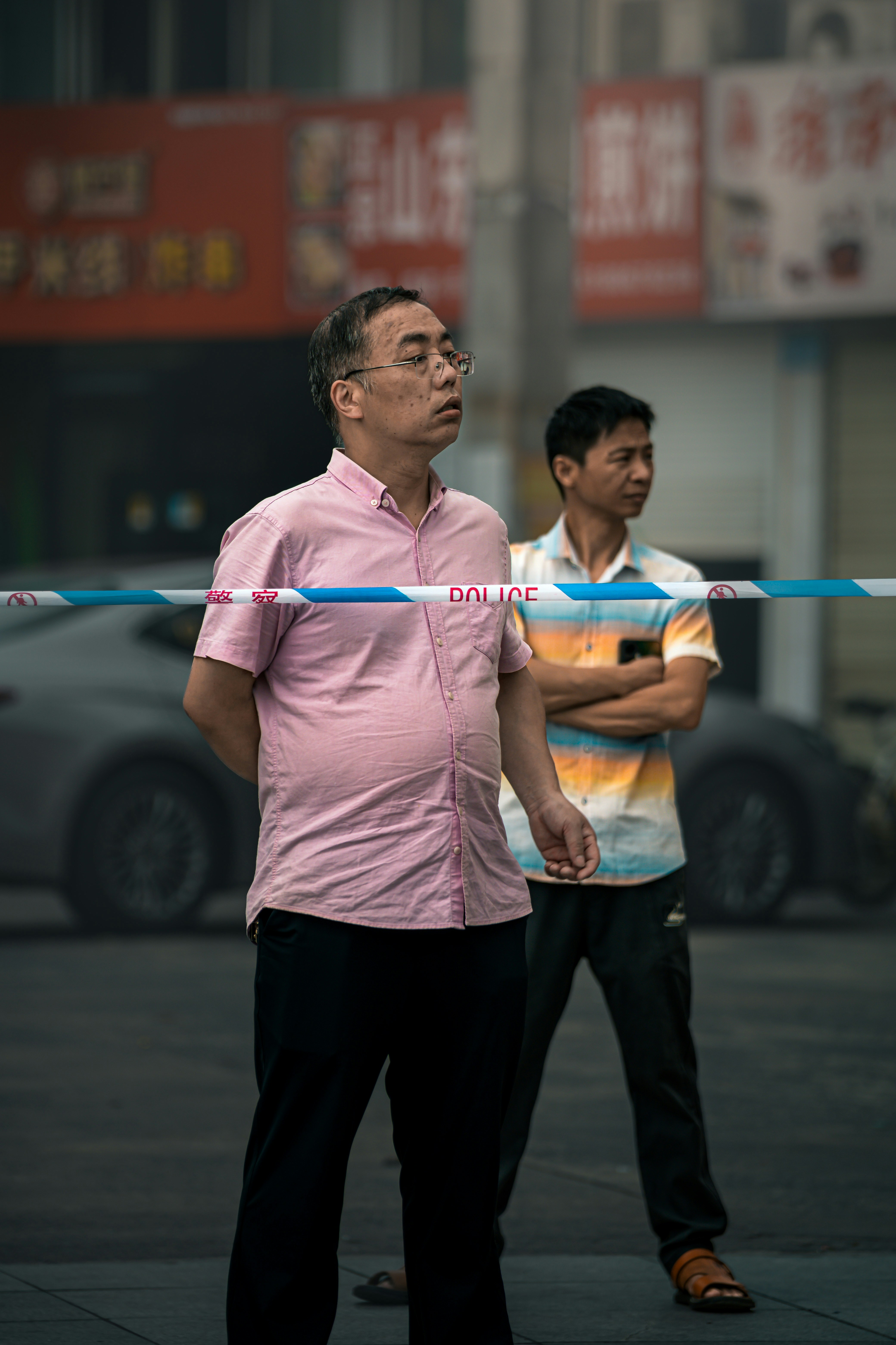Quiet Vigil: A Pink Shirted Figure Under Police Tape