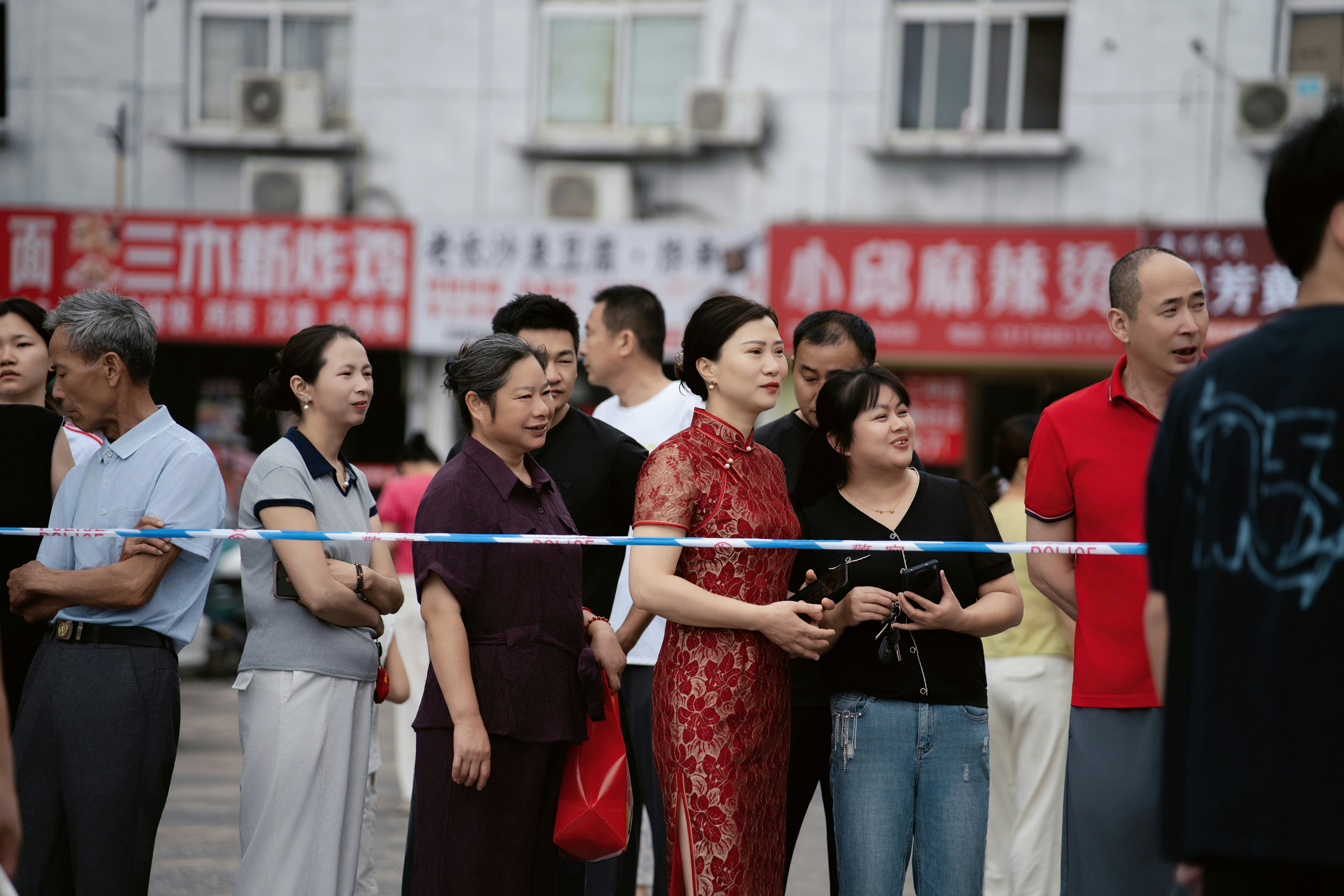 Red cheers and quiet tension: a crowd waits behind a taped line