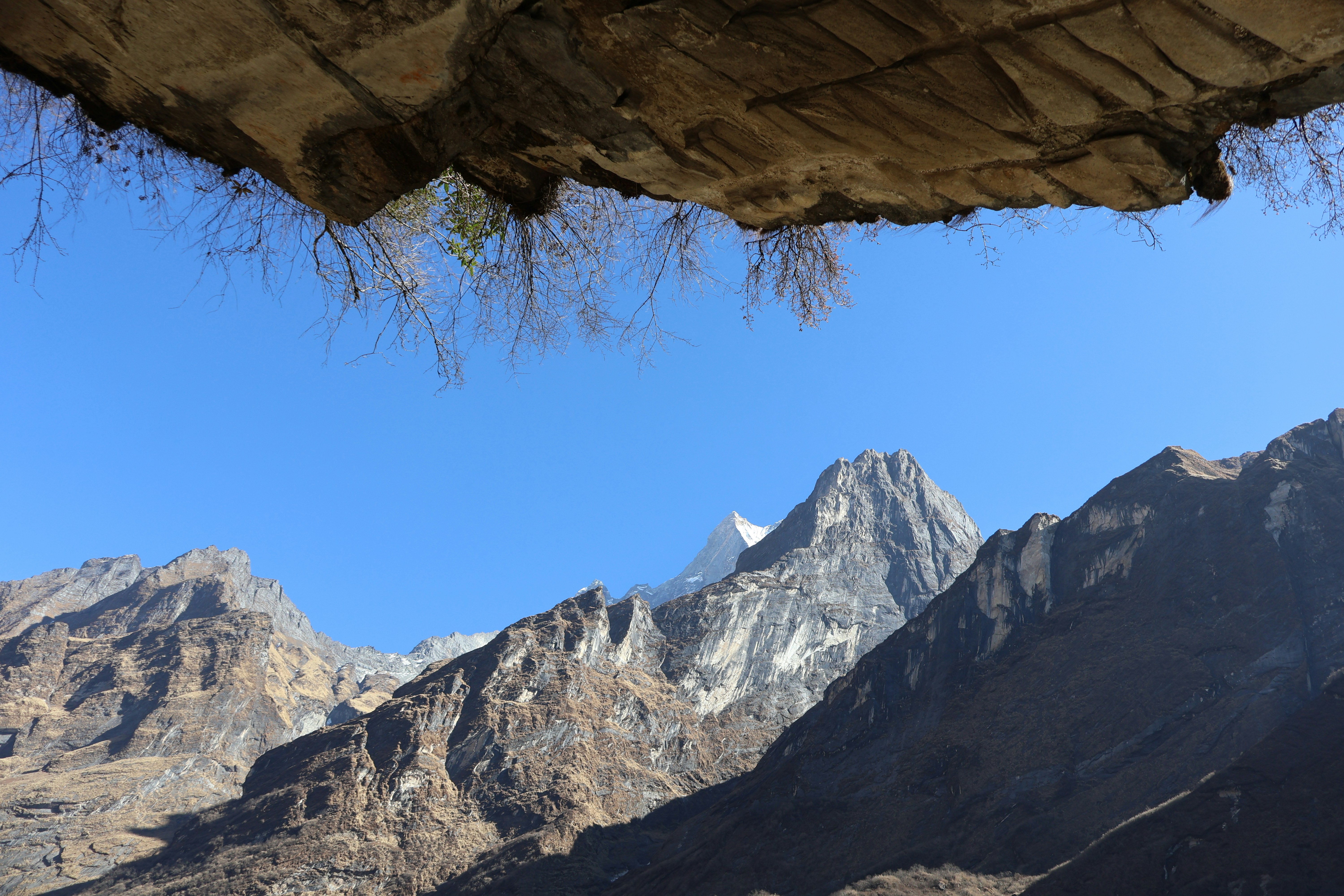 Overhang View: Snow-Crowned Peaks Beneath a Carved Canyon Ceiling