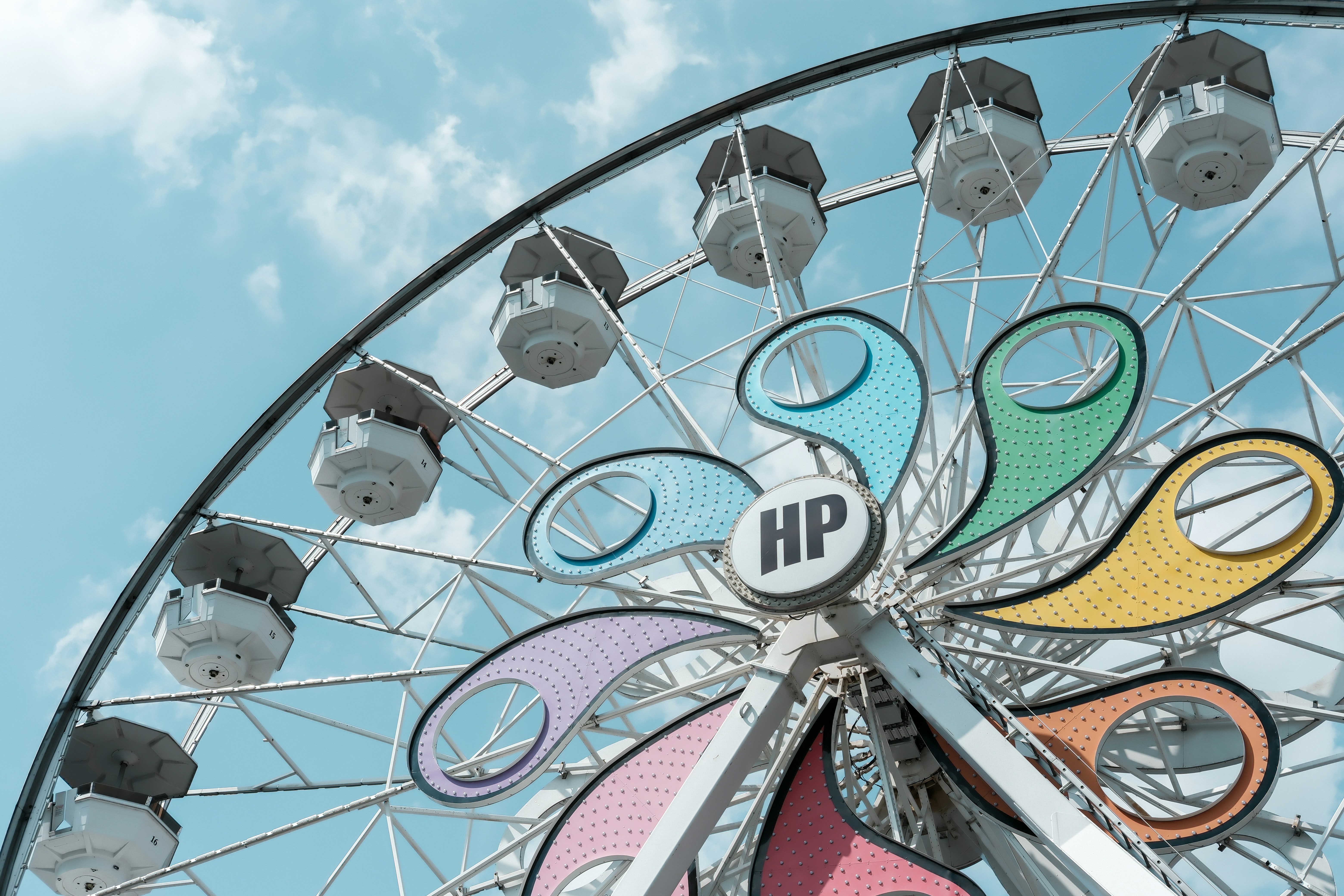Colorful ferris wheel with 'hp' logo against a blue sky.