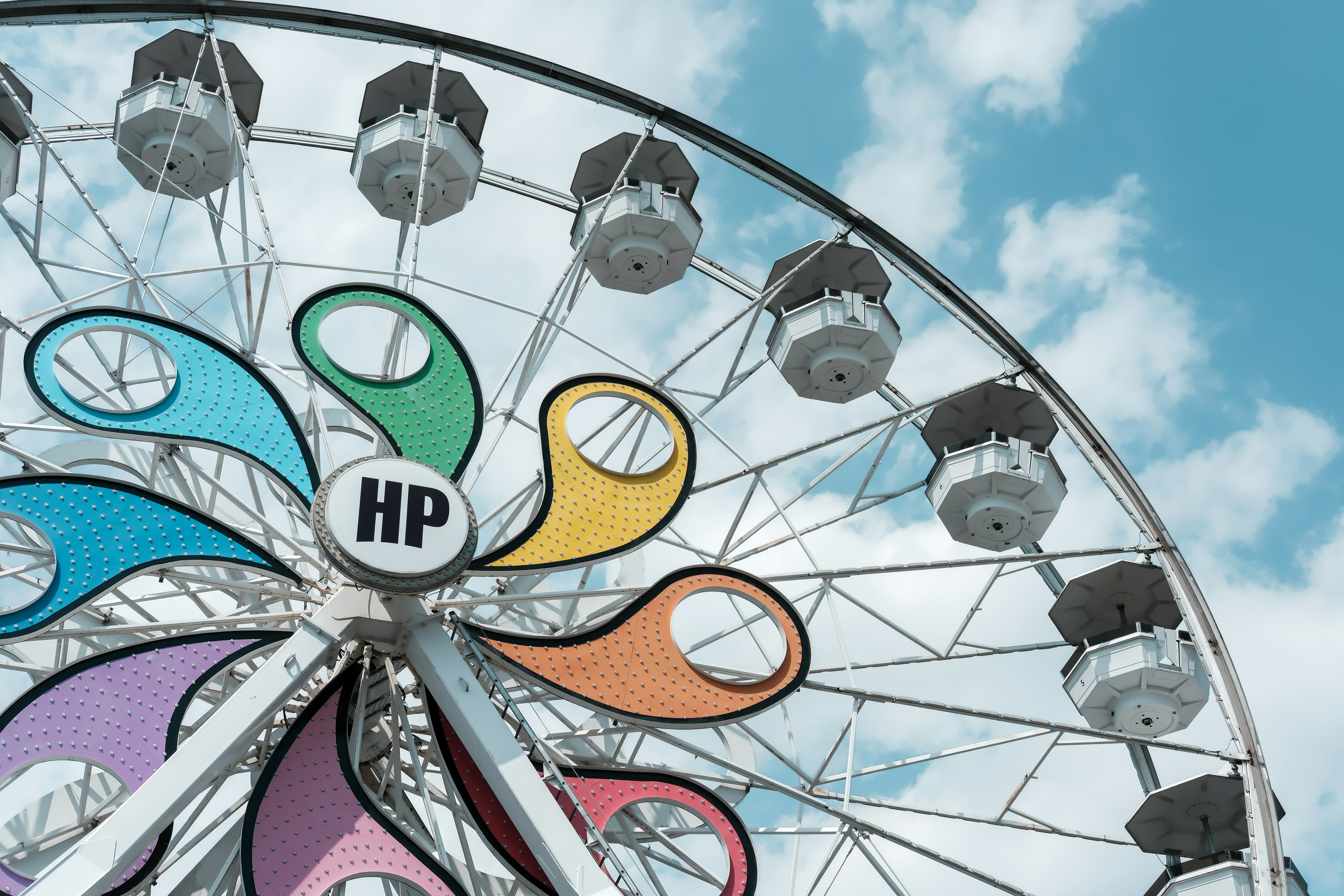Ferris wheel with colorful spokes and "hp" logo against sky.