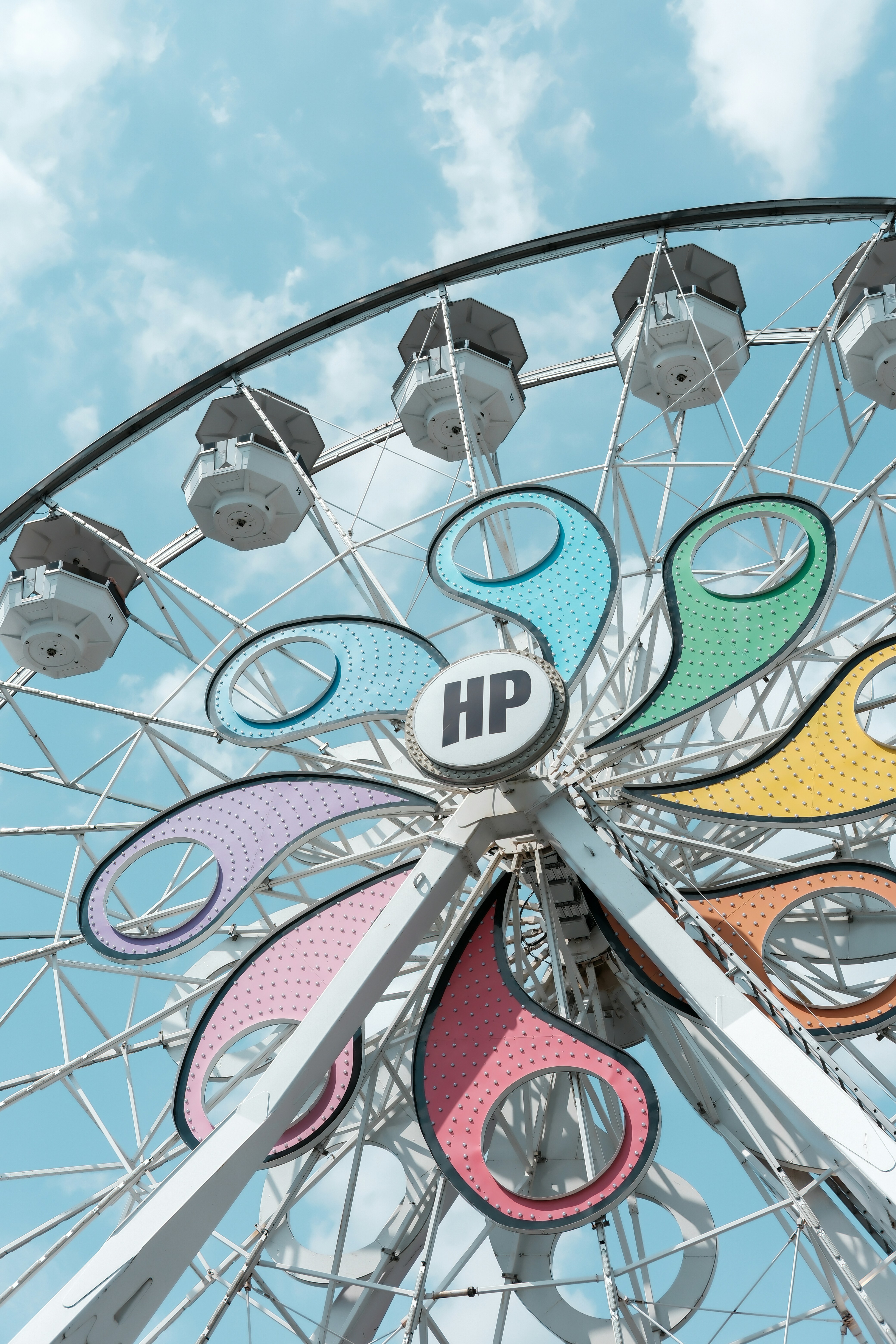 A colorful ferris wheel against a blue sky with clouds.