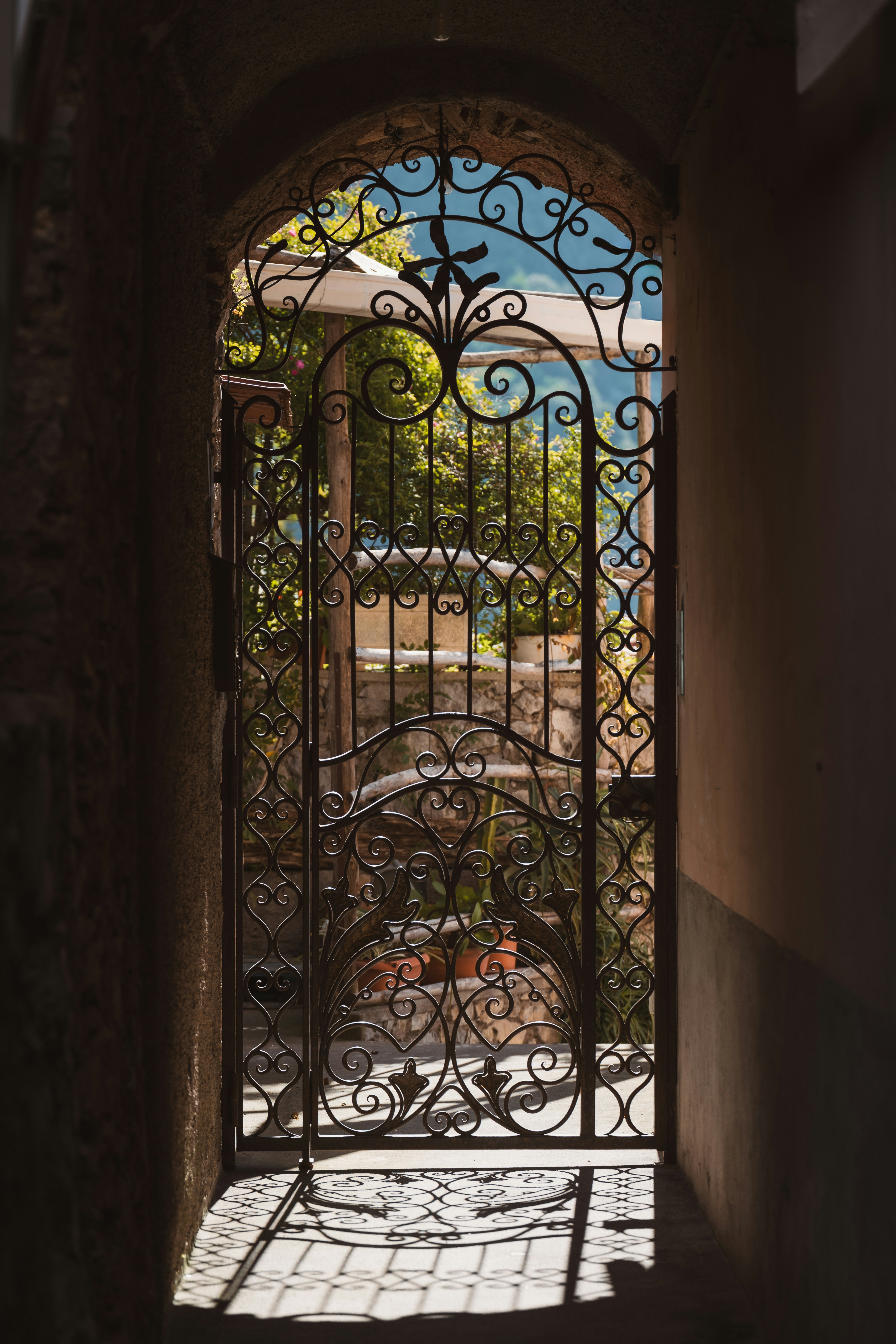 Sunlit wrought-iron doorway framed by stone arch