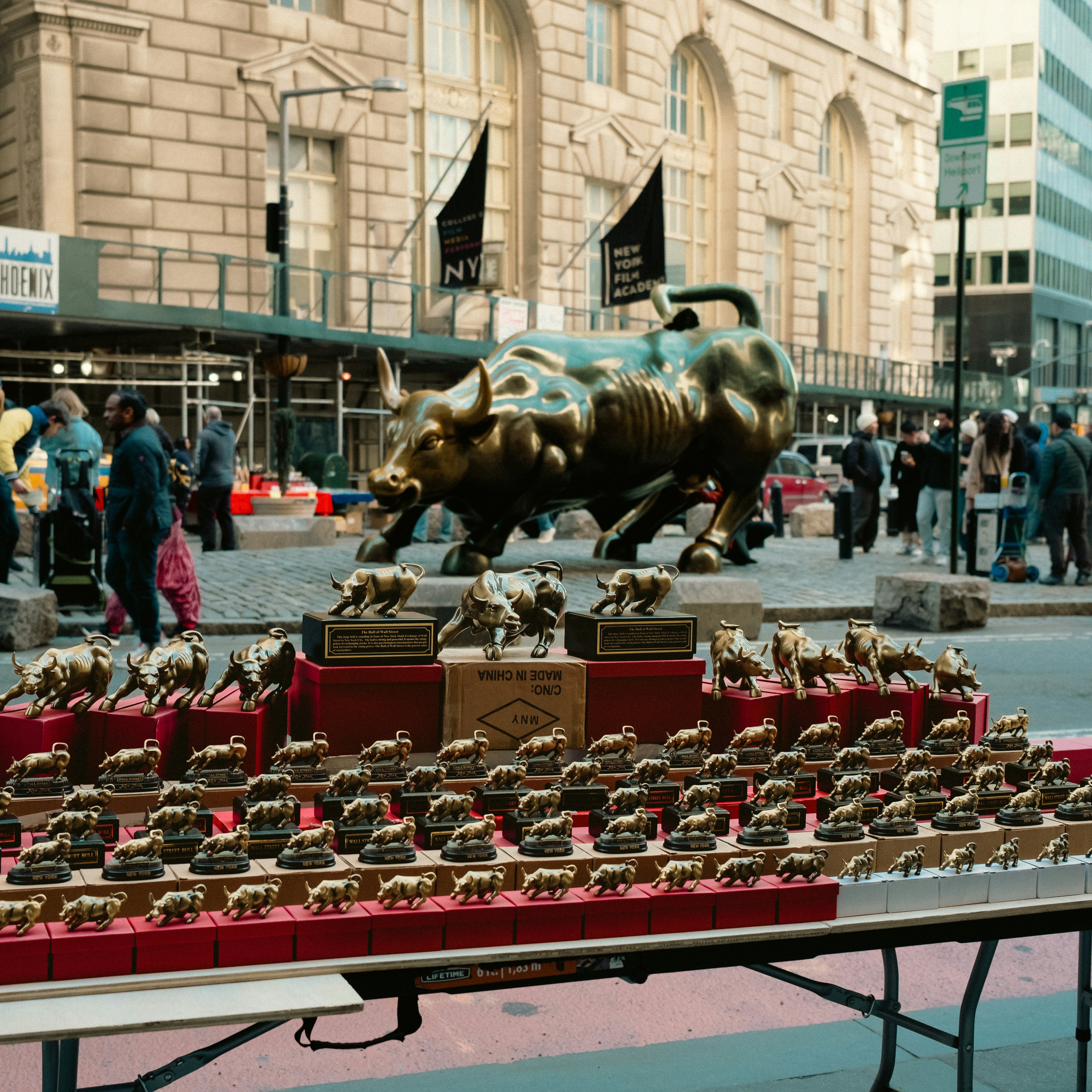 Iconic charging bull statue surrounded by numerous small bull figurines.